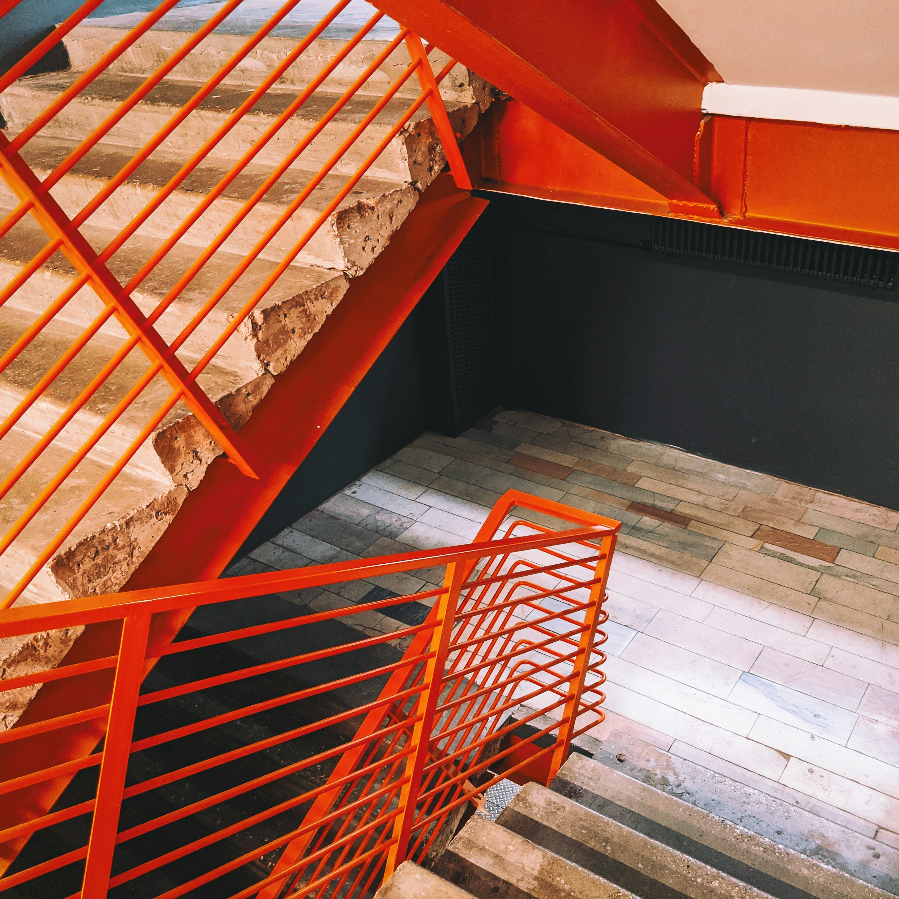 A staircase with orange railings next to a tiled floor photo – Free ...