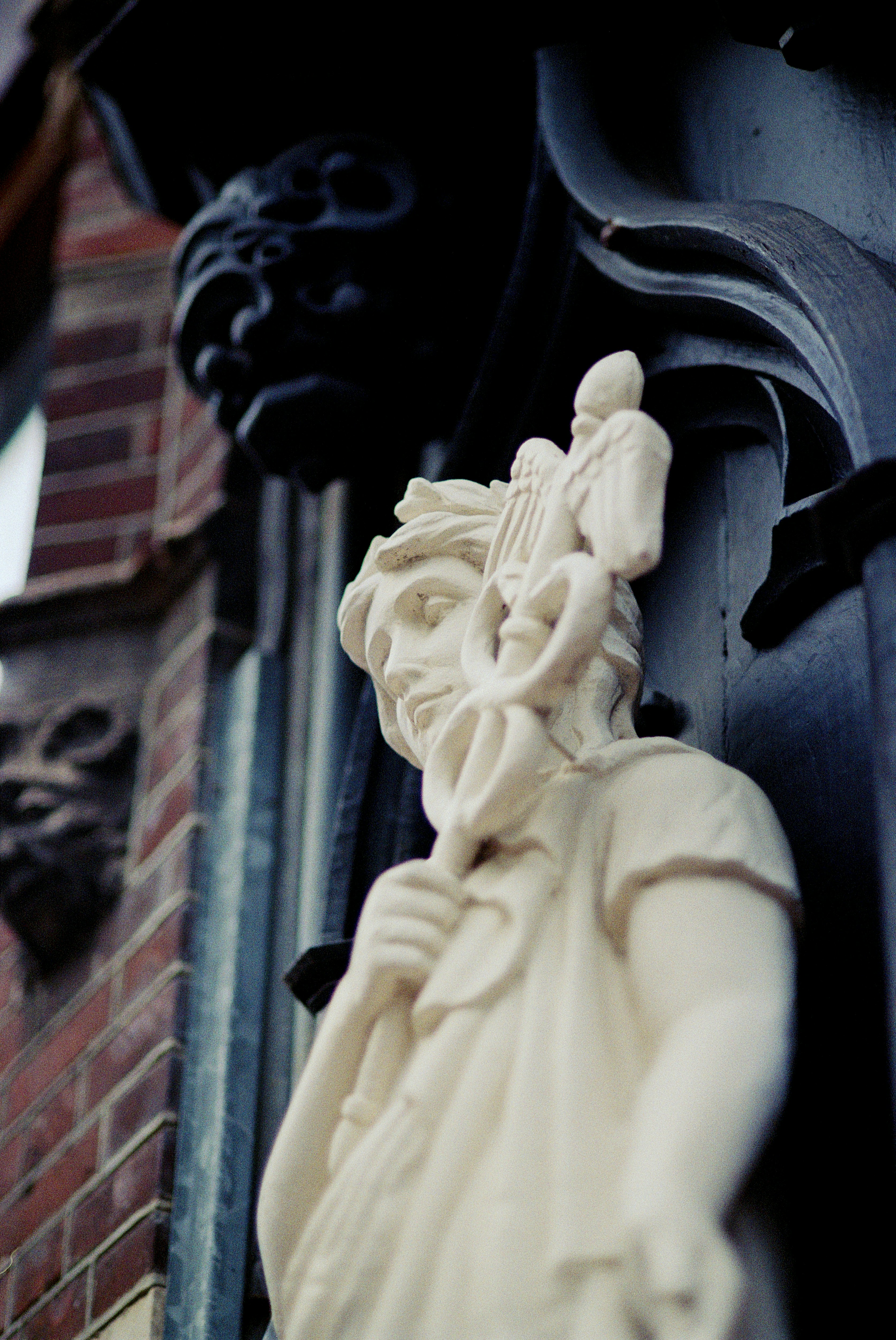 Threshold Figure: Ivory Statue Framed by Brick and Wrought Iron