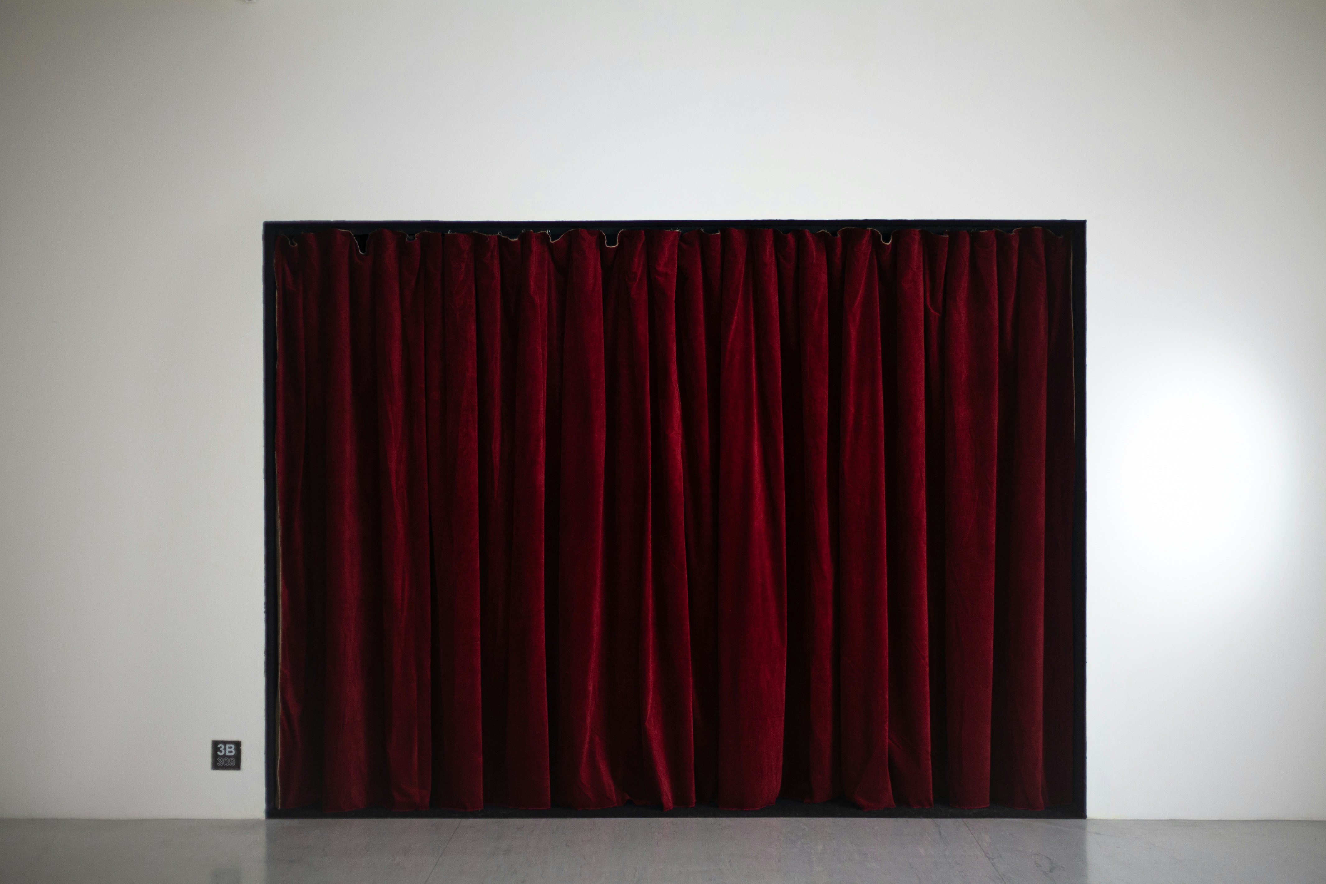 Midnight Velvet: a solitary red curtain in a stark white gallery