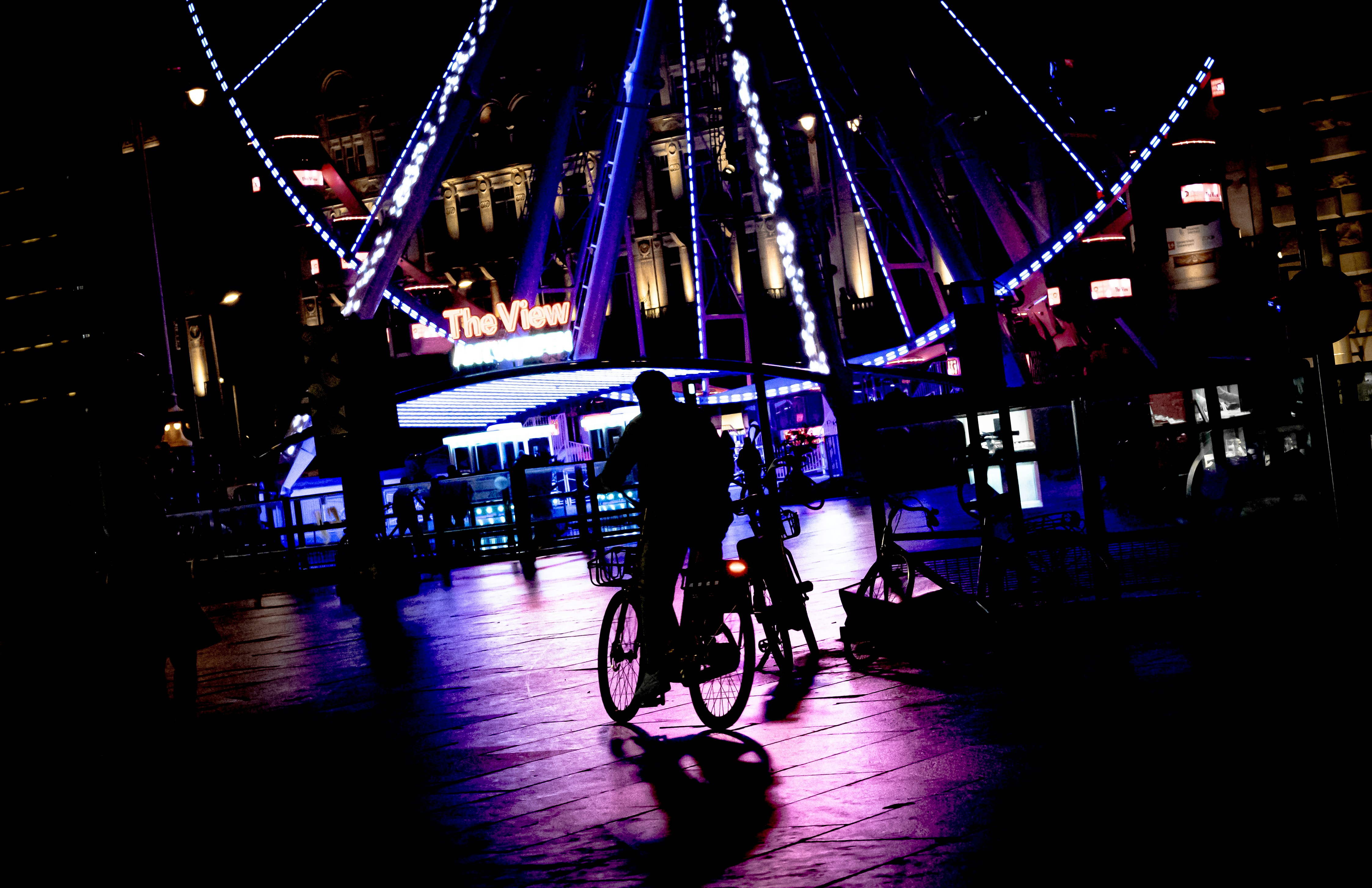 Midnight Neon: Silhouette of a Cyclist Beneath the Blue Ferris Wheel