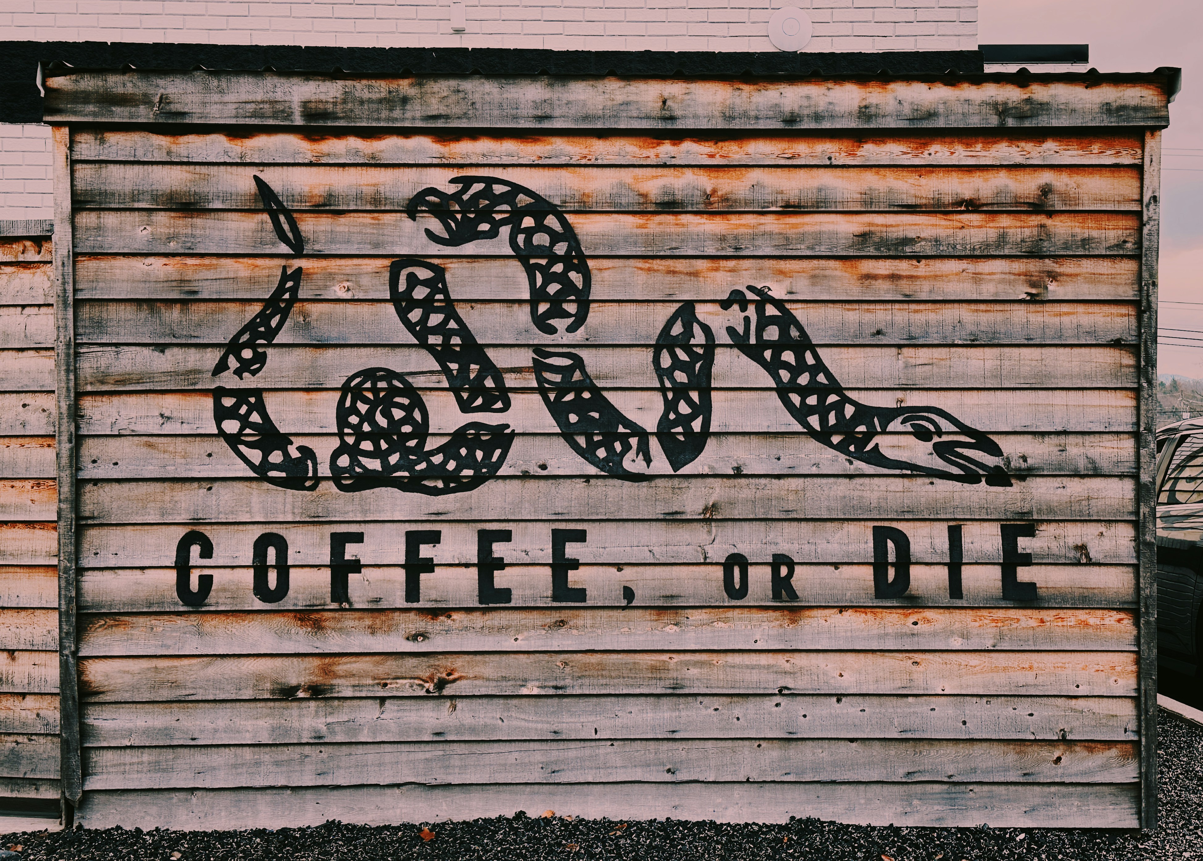 Rustic Graffiti: Coffee, or Die etched on a weathered shutter