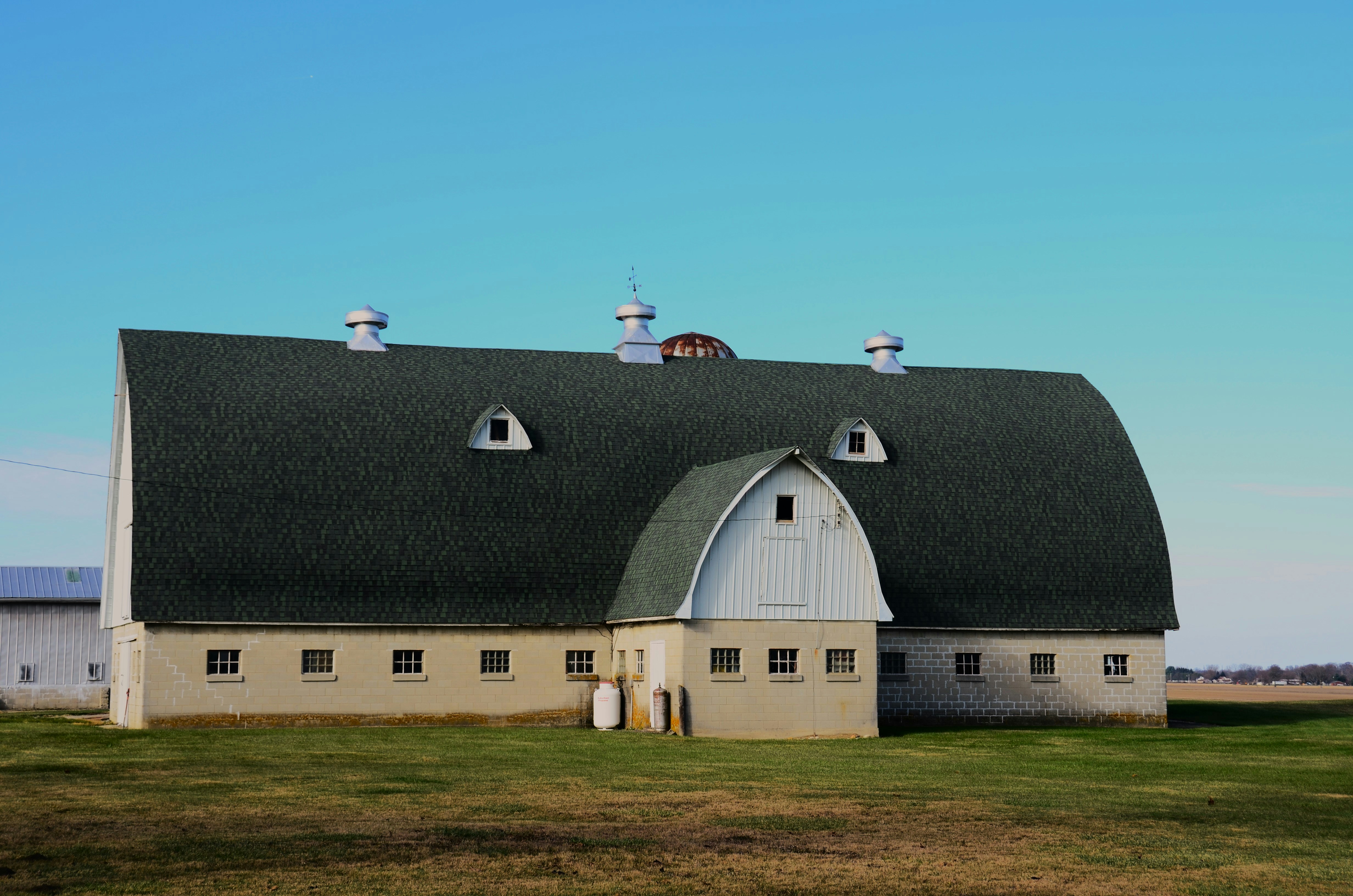 A large white barn sitting on top of a lush green field photo – Free ...