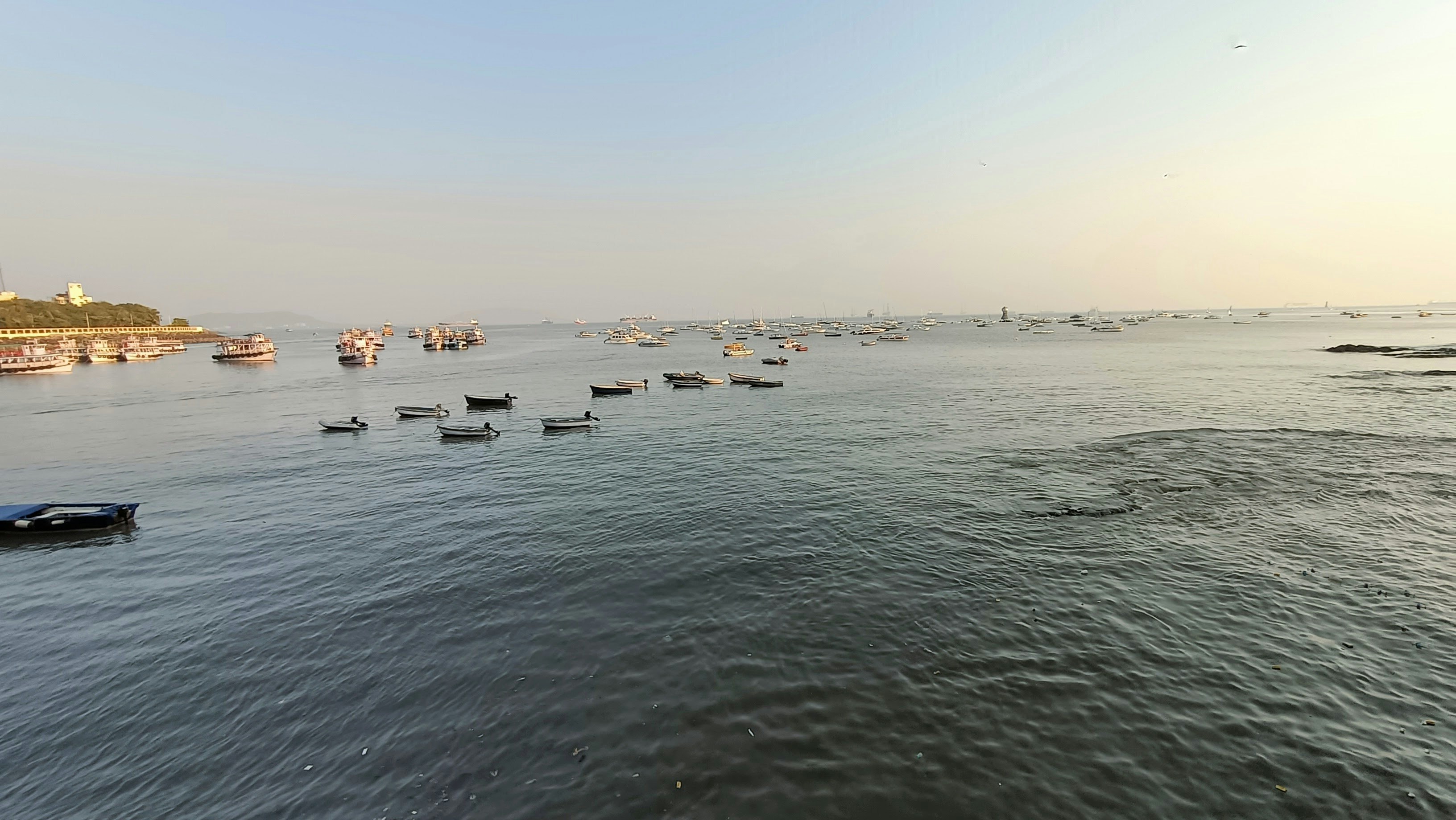 Numerous boats navigate a serene harbor at dusk, reflecting the soft hues of the evening sky. The scene captures the essence of maritime life.