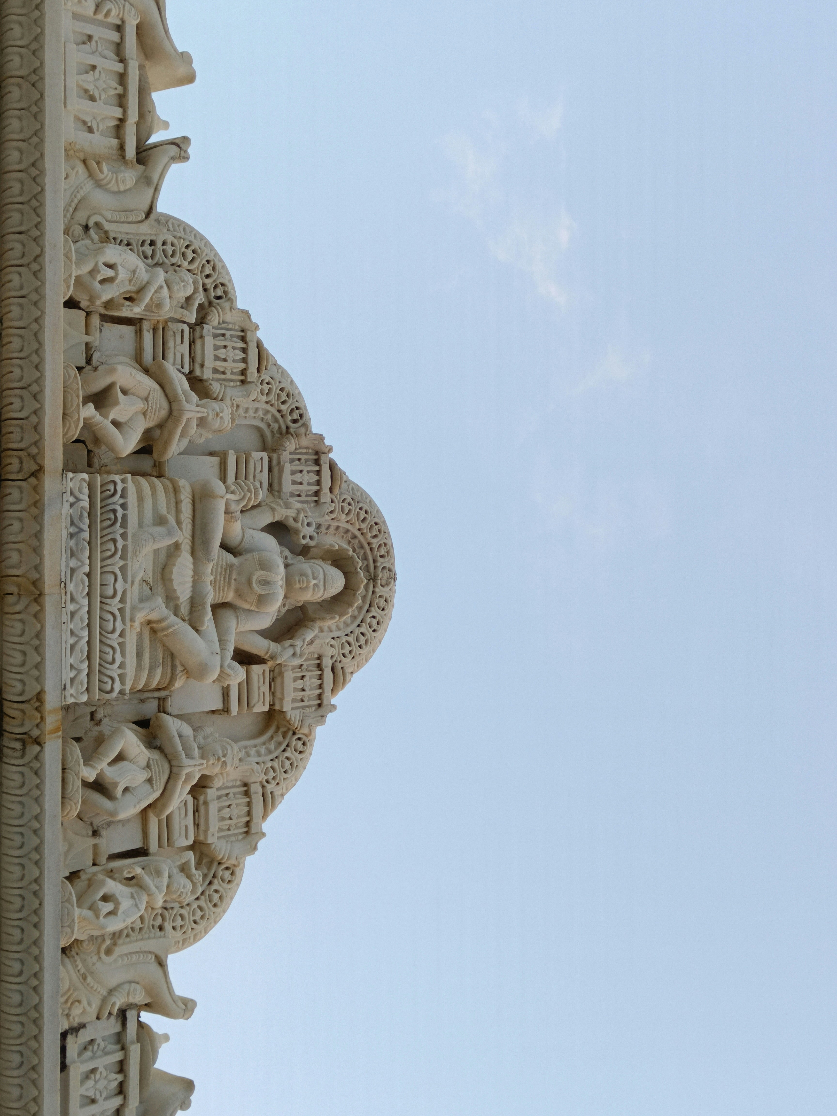 Intricate stone carvings depicting deities and motifs adorning a temple facade against a clear sky.