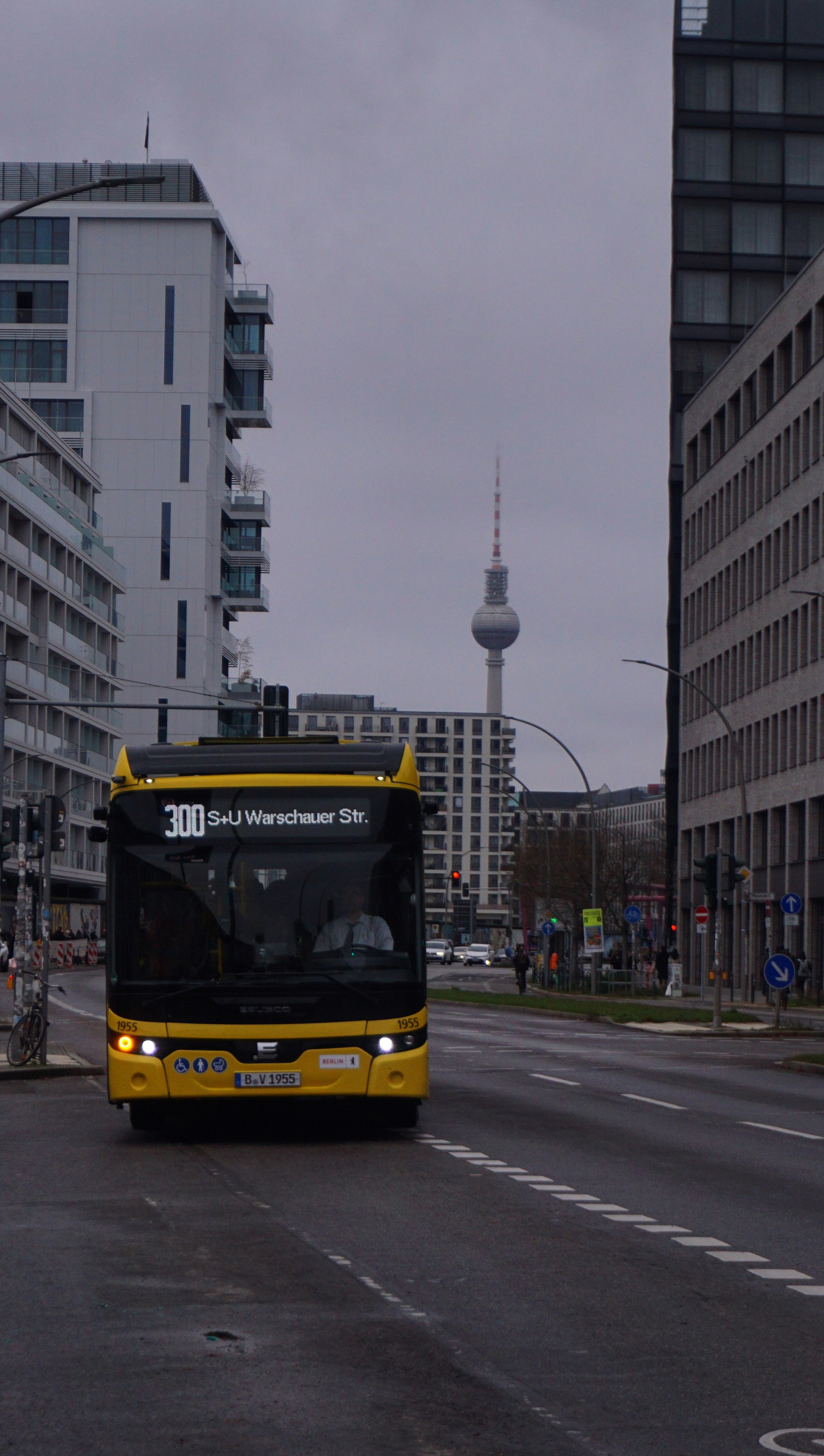 A yellow bus driving down a street next to tall buildings photo – Free ...