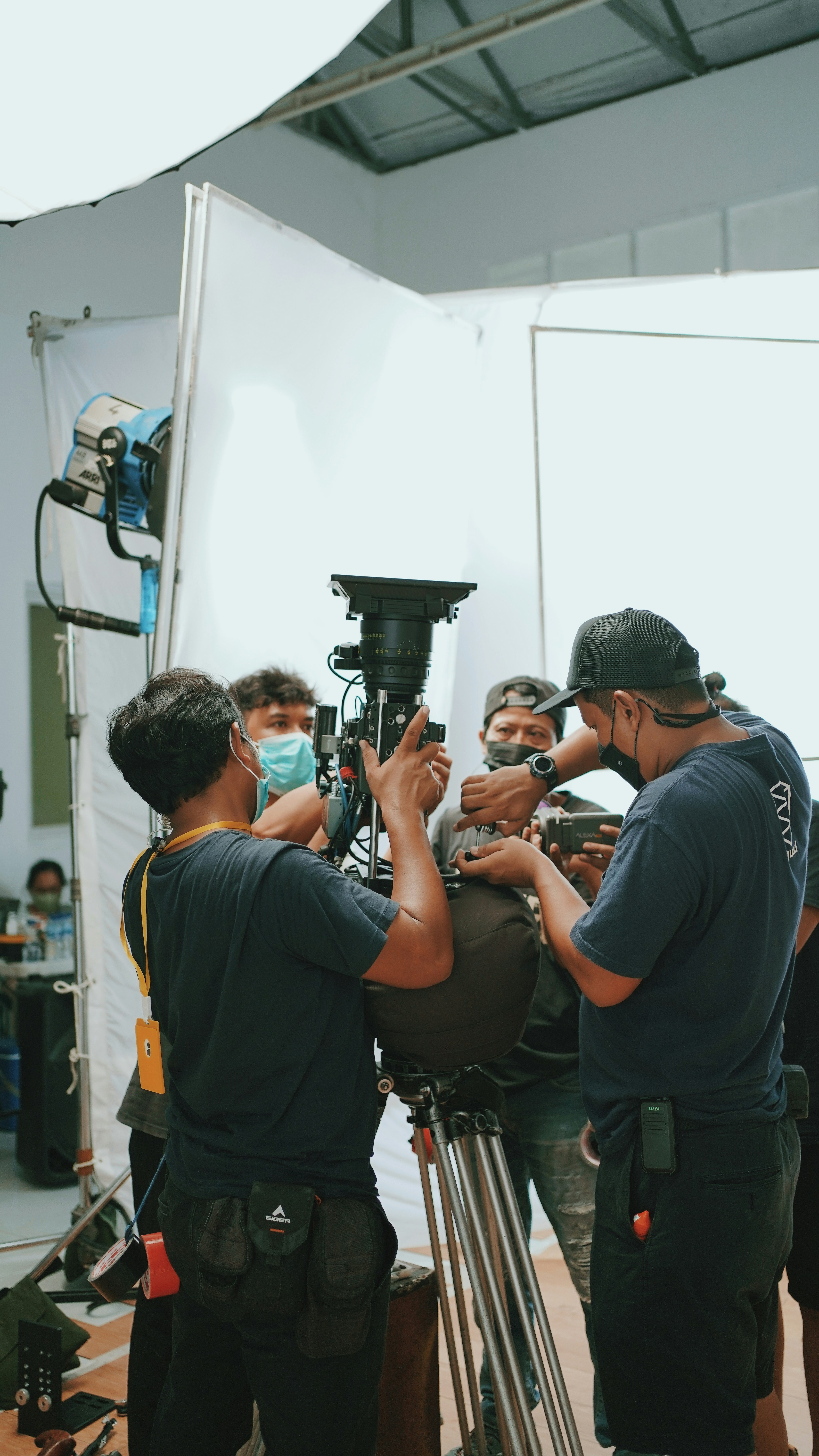 A group of men standing around a camera photo – Free Woman Image on ...