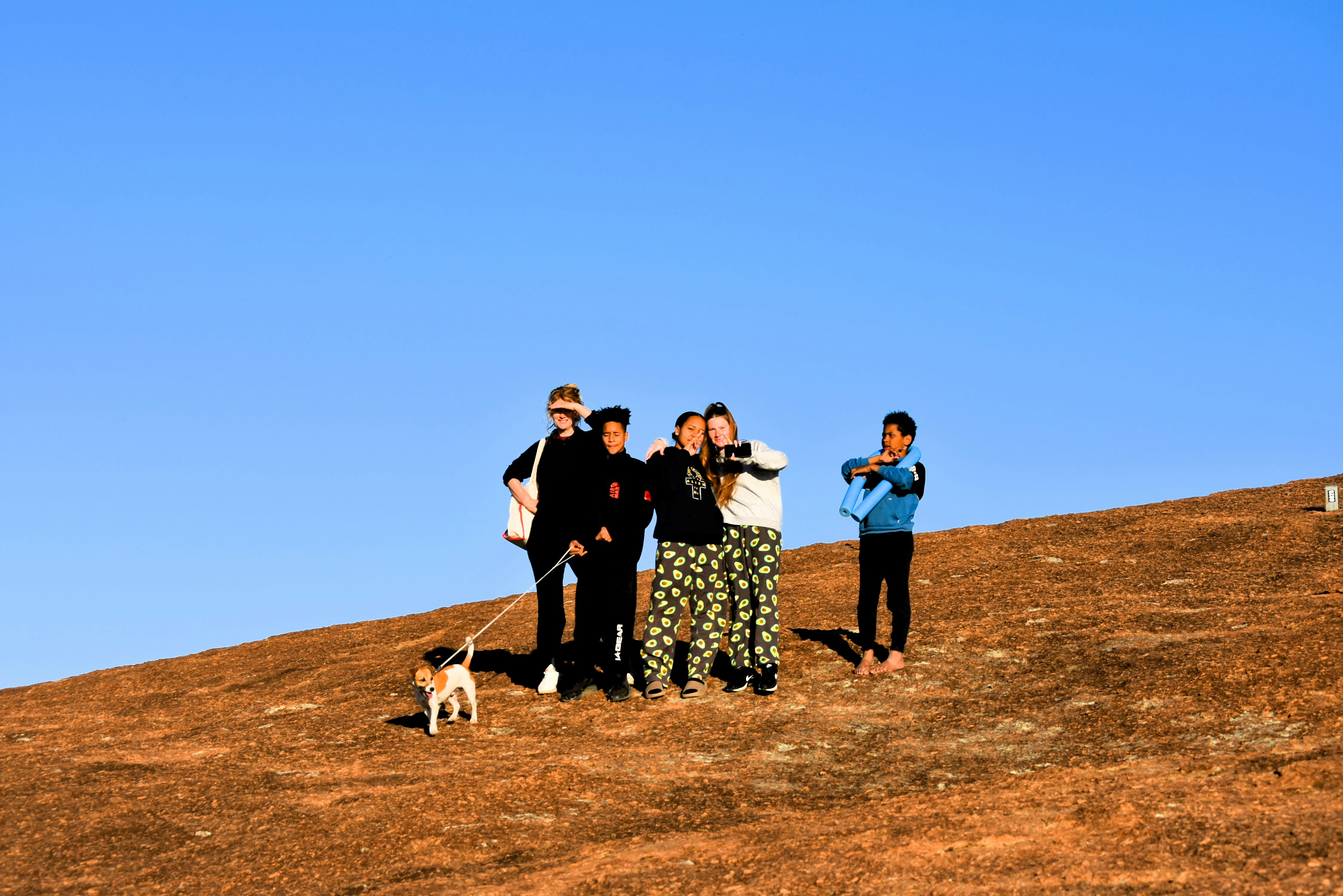 Dune-side Reunion: A Sunlit Group Portrait with a Leashed Beagle Against a Clear Sky