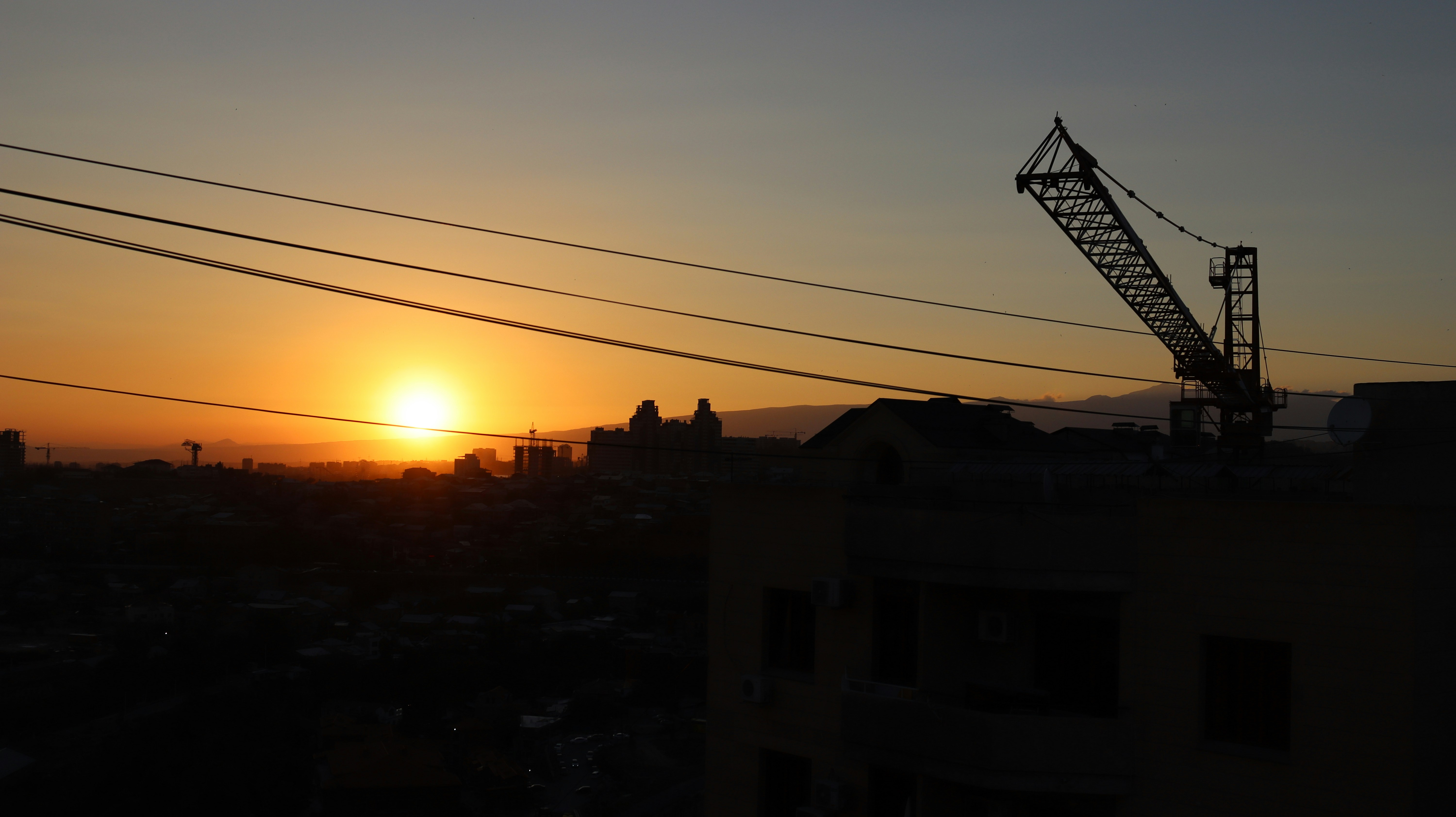 Horizon Fire: Sunset Silhouettes and a Crane over a Quiet City