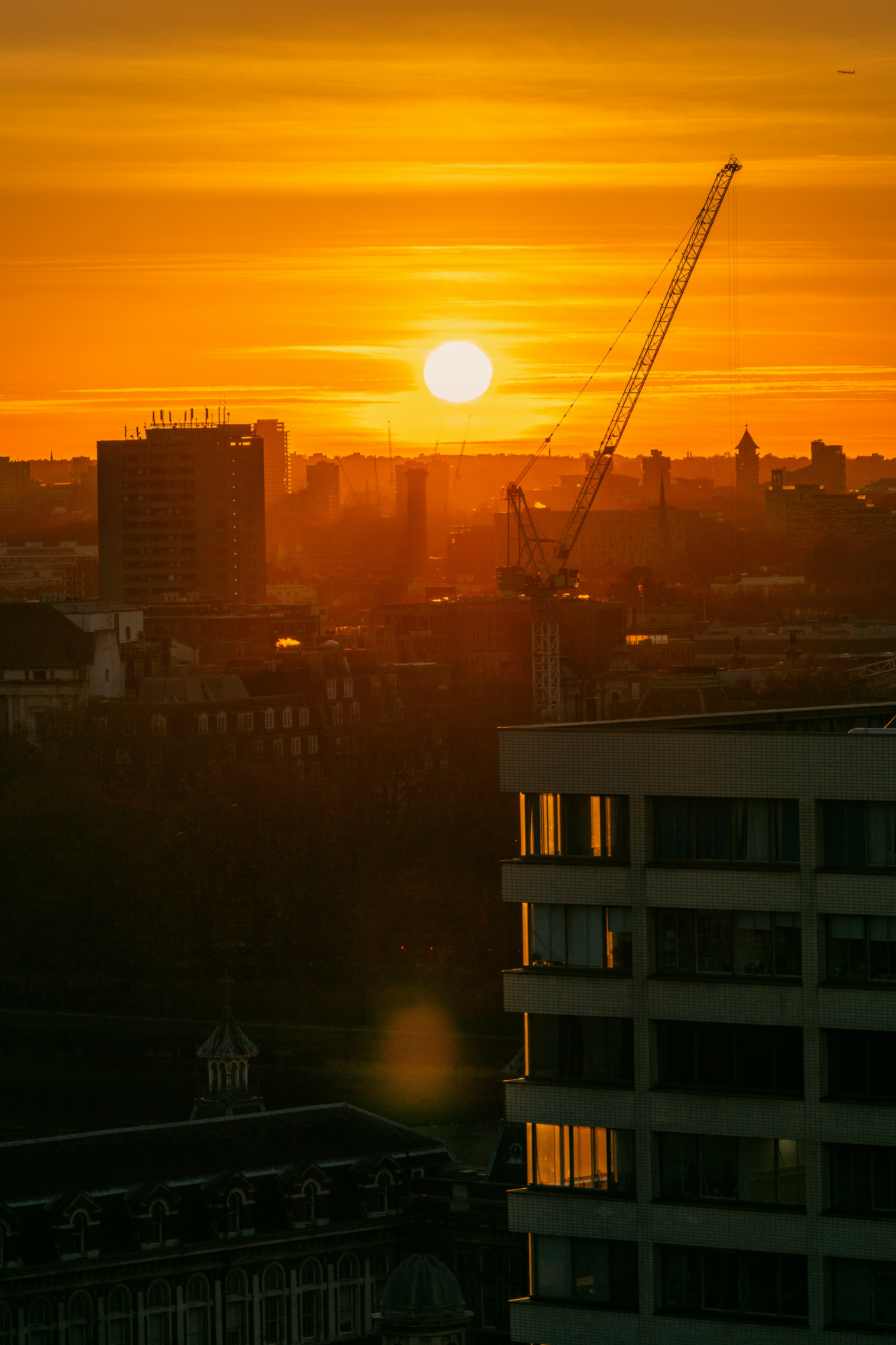 Molten Gold Over the City: Sunset Silhouette of Crane and Skyscrapers