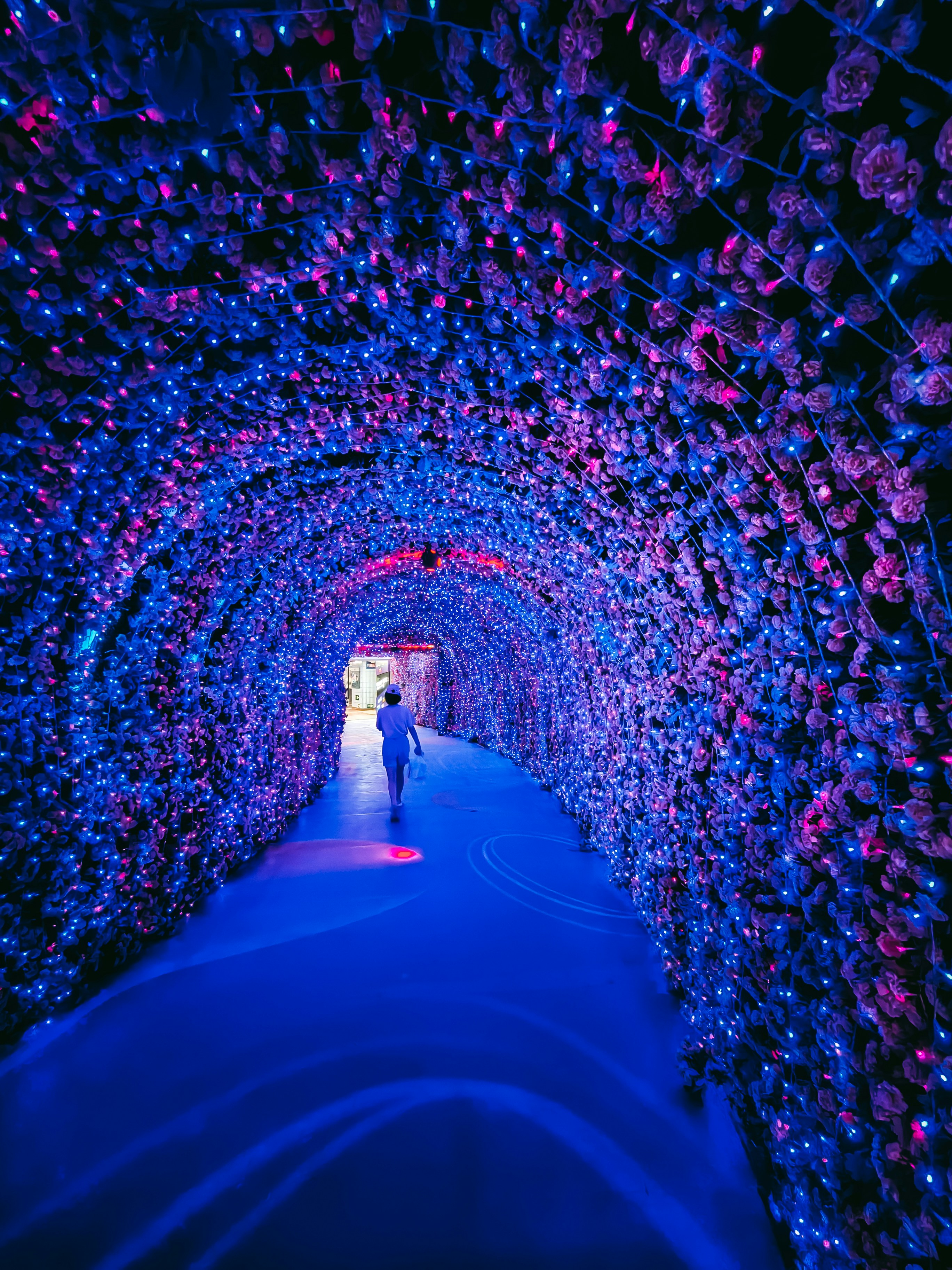 Neon Bloom Tunnel: A lone figure walks toward a violet-lit exit