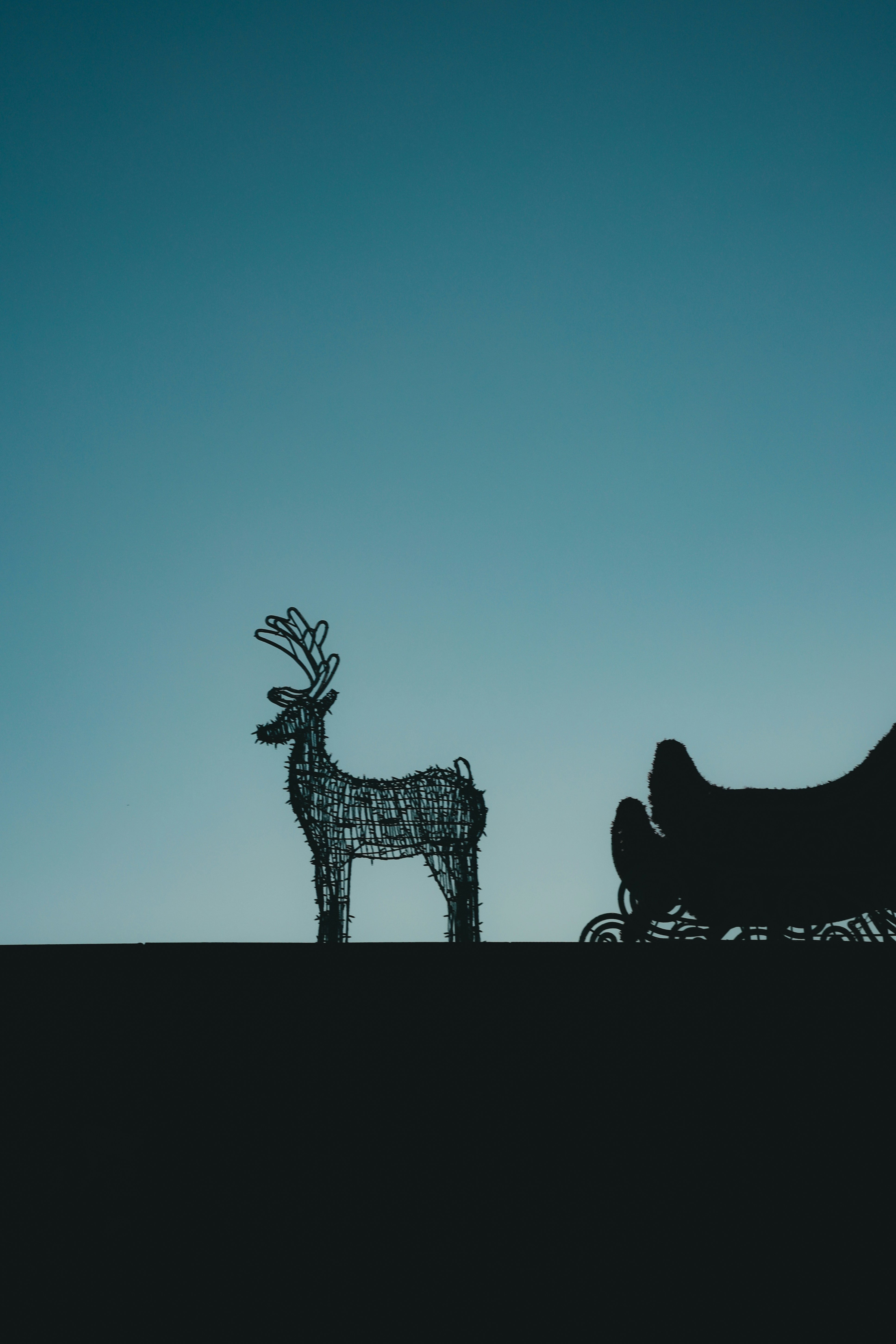 Dusk Silhouette: Wireframe Reindeer Beside a Rooftop Sleigh