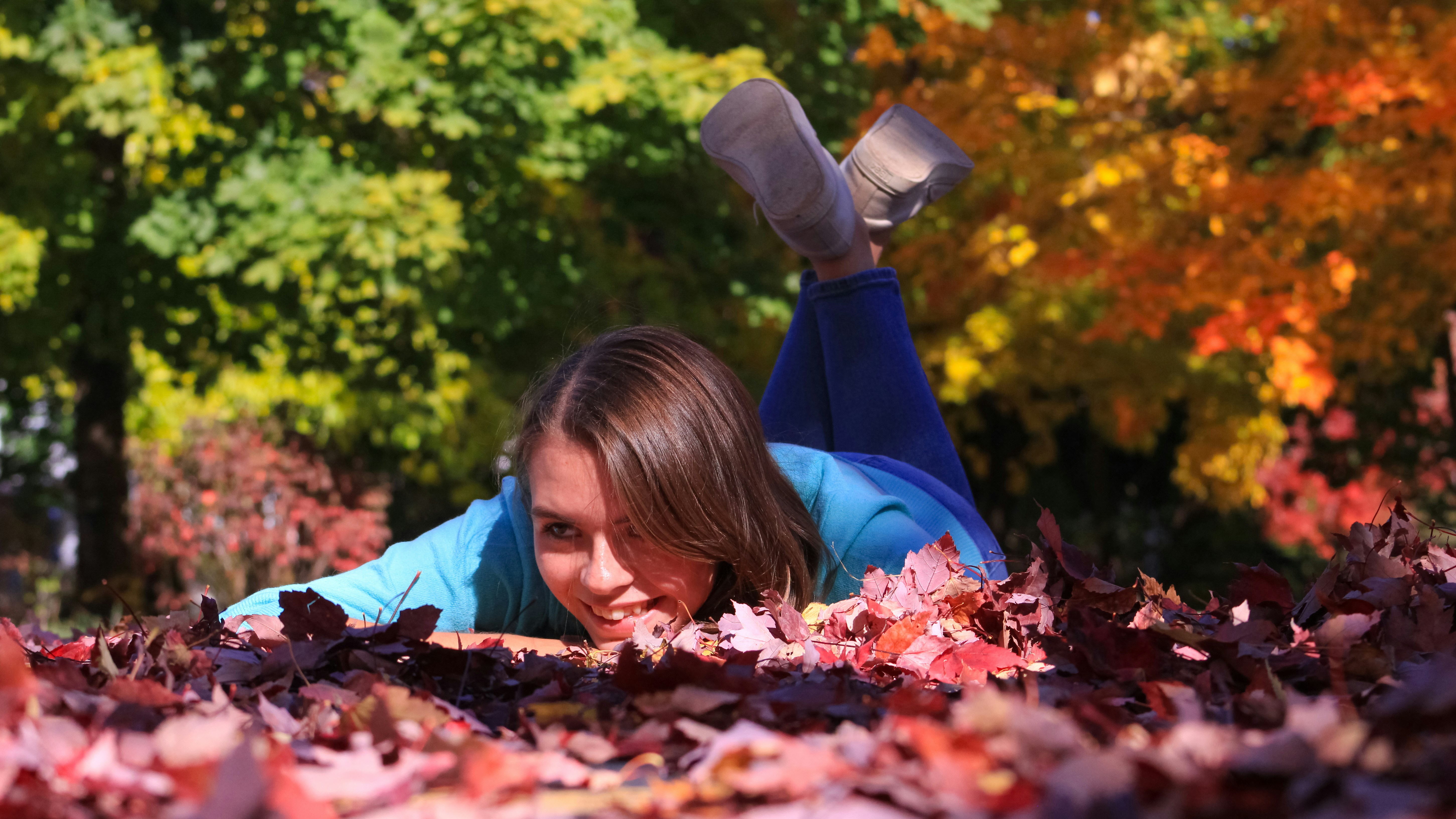 a woman laying on her back in a pile of leaves