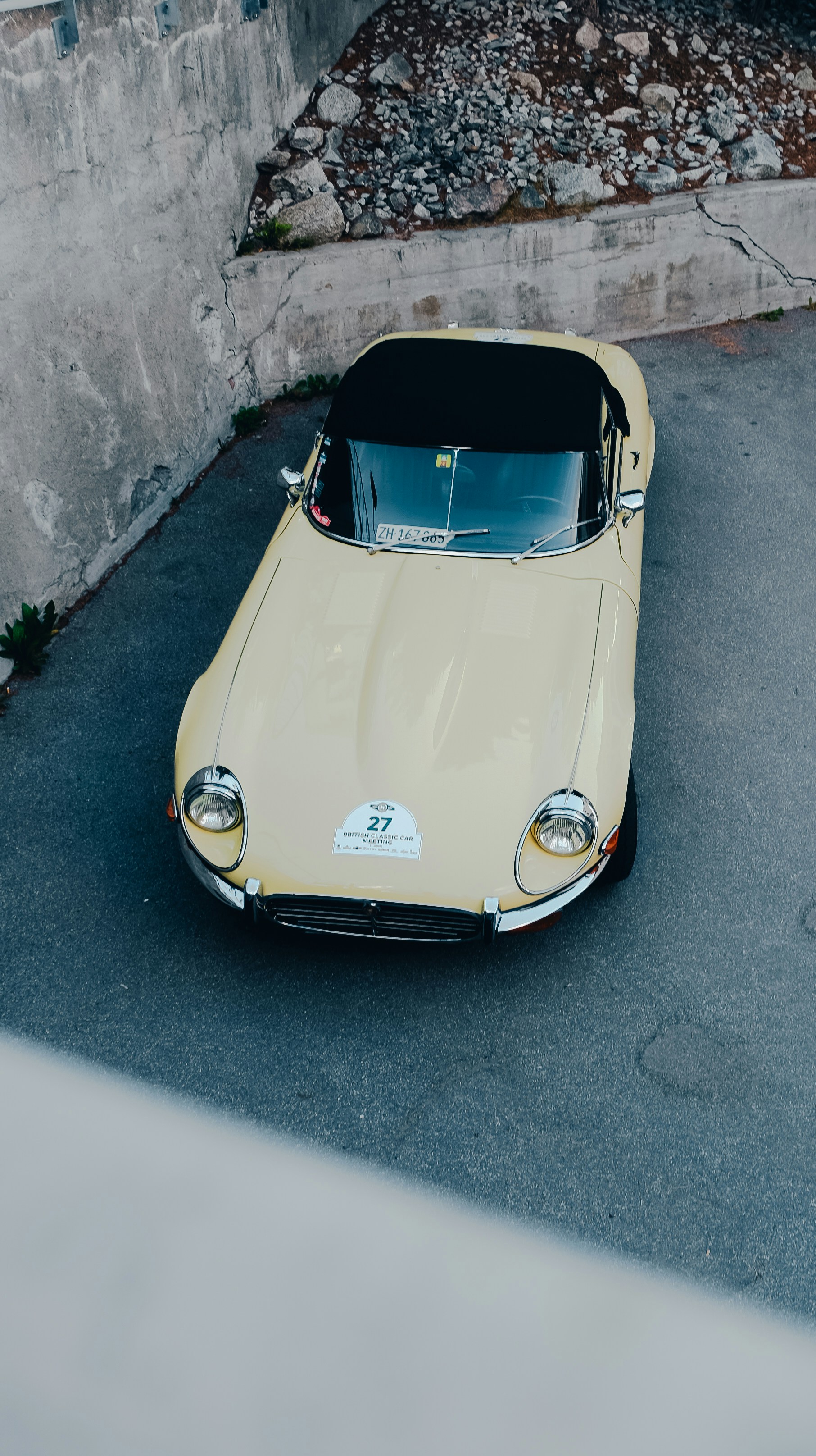 Aerial View: Cream Jaguar E-Type Resting by a Weathered Wall