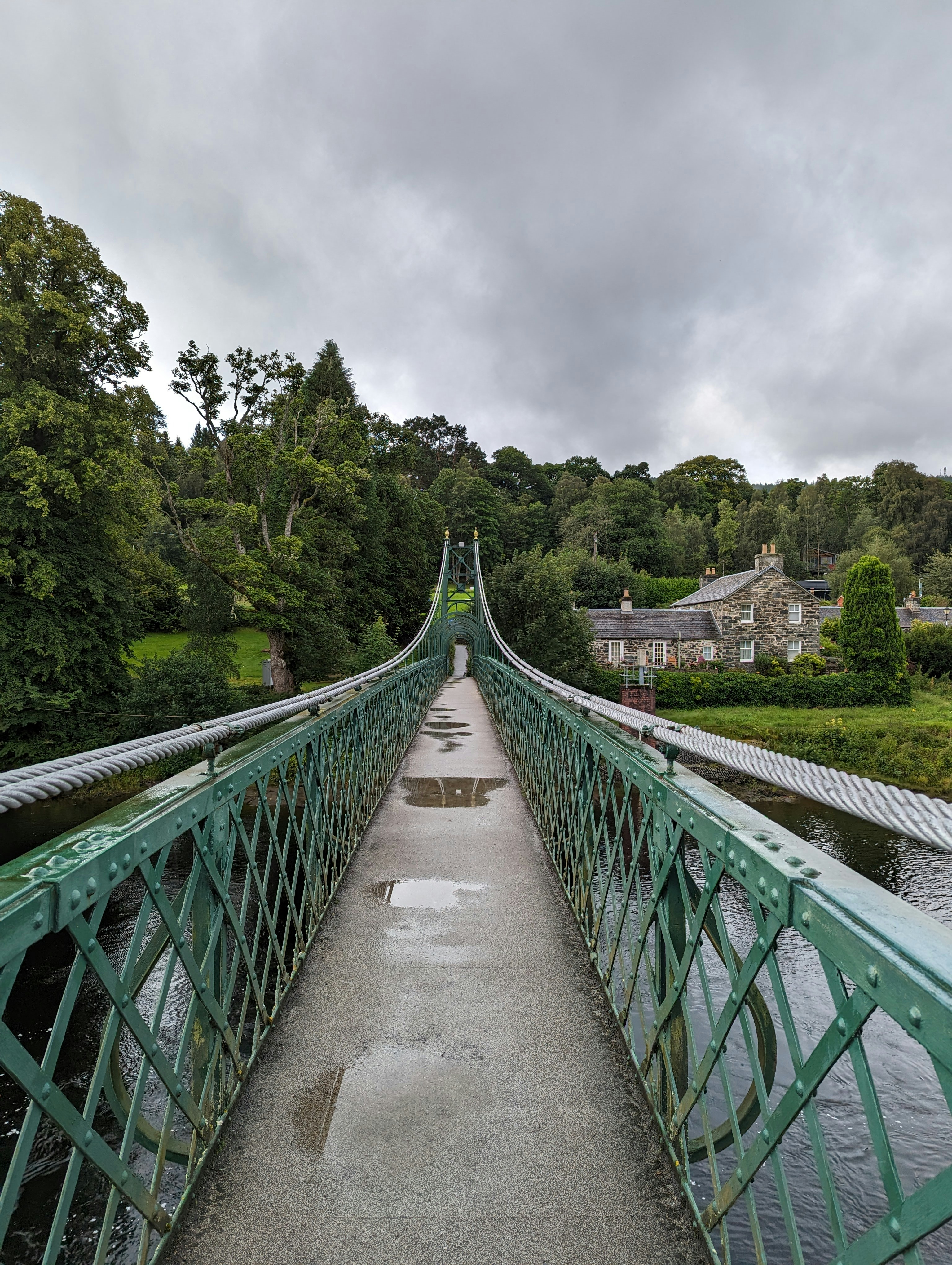 Green Suspension Bridge: A Narrow Path to a Quiet Stone Cottage