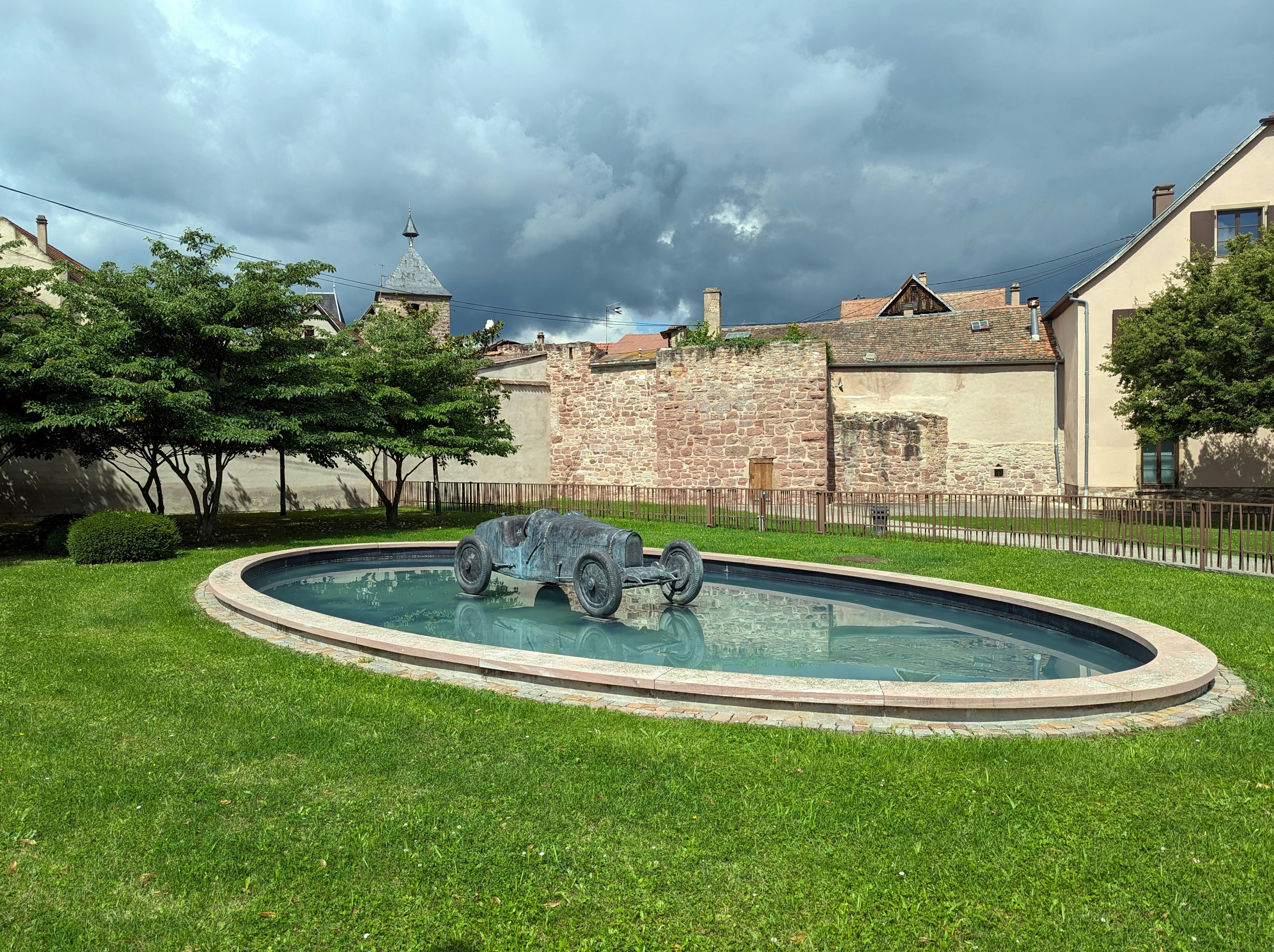 Circular Fountain in the Green: Time-Worn Walls Framed by Storm-Ready Clouds