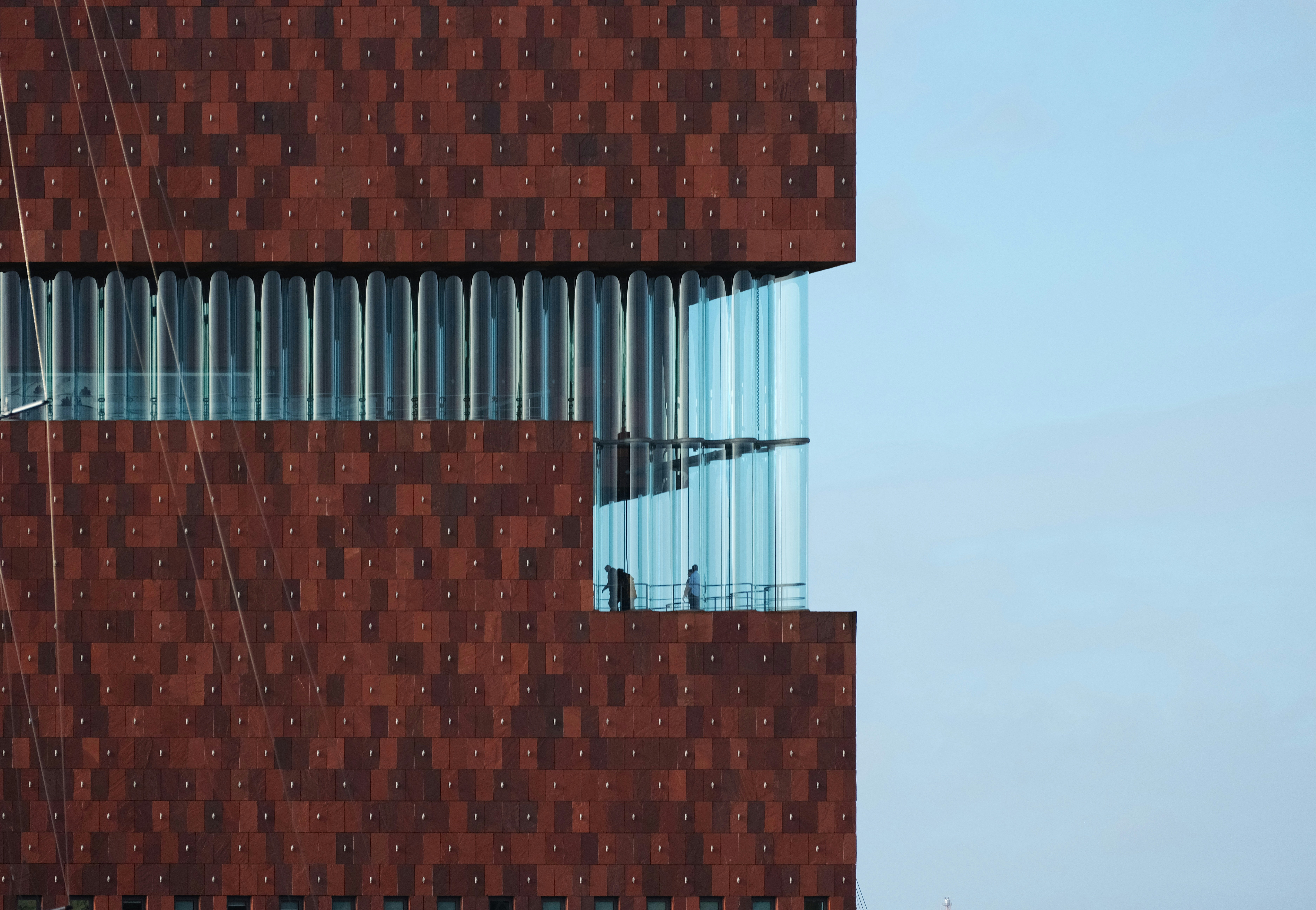 Glass Ribbon Through Rust-Red Facade