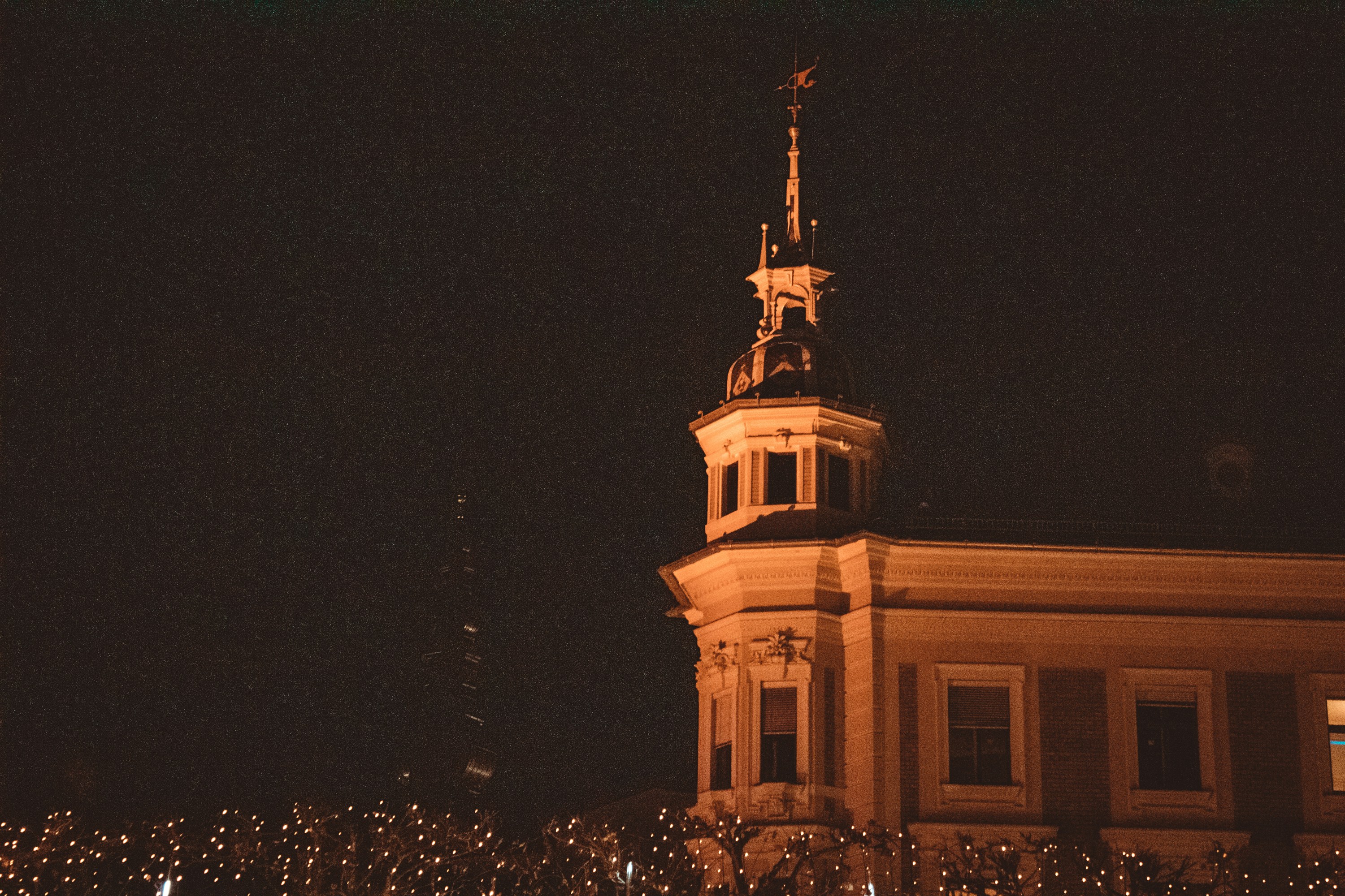 Historic building adorned with warm lights, showcasing intricate architectural details against a dark sky.