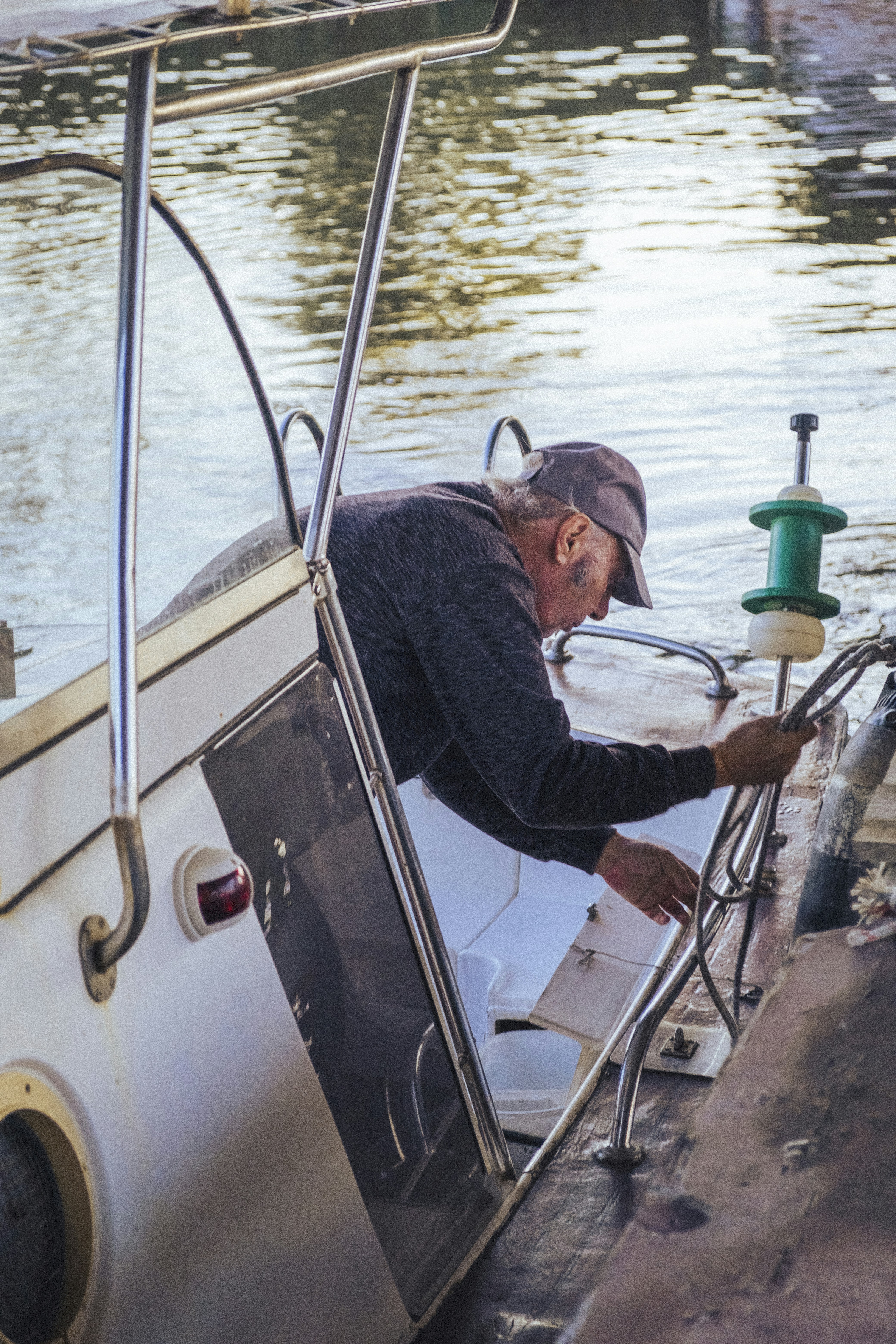 Dockside Precision: Deckhand Tends a Small Boat by Quiet Reflections