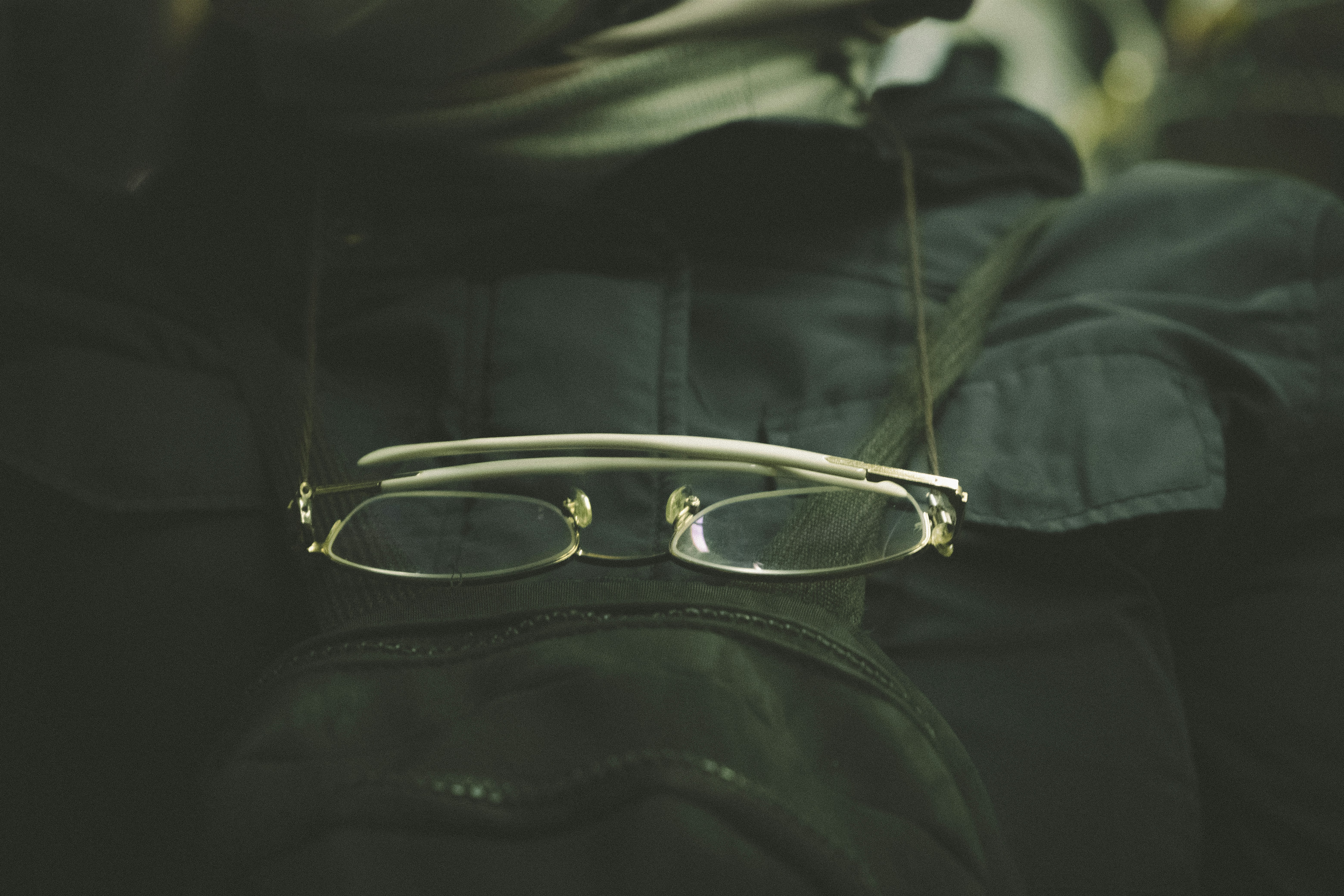 Glasses at Rest on a Quilted Surface Under Muted Green Light