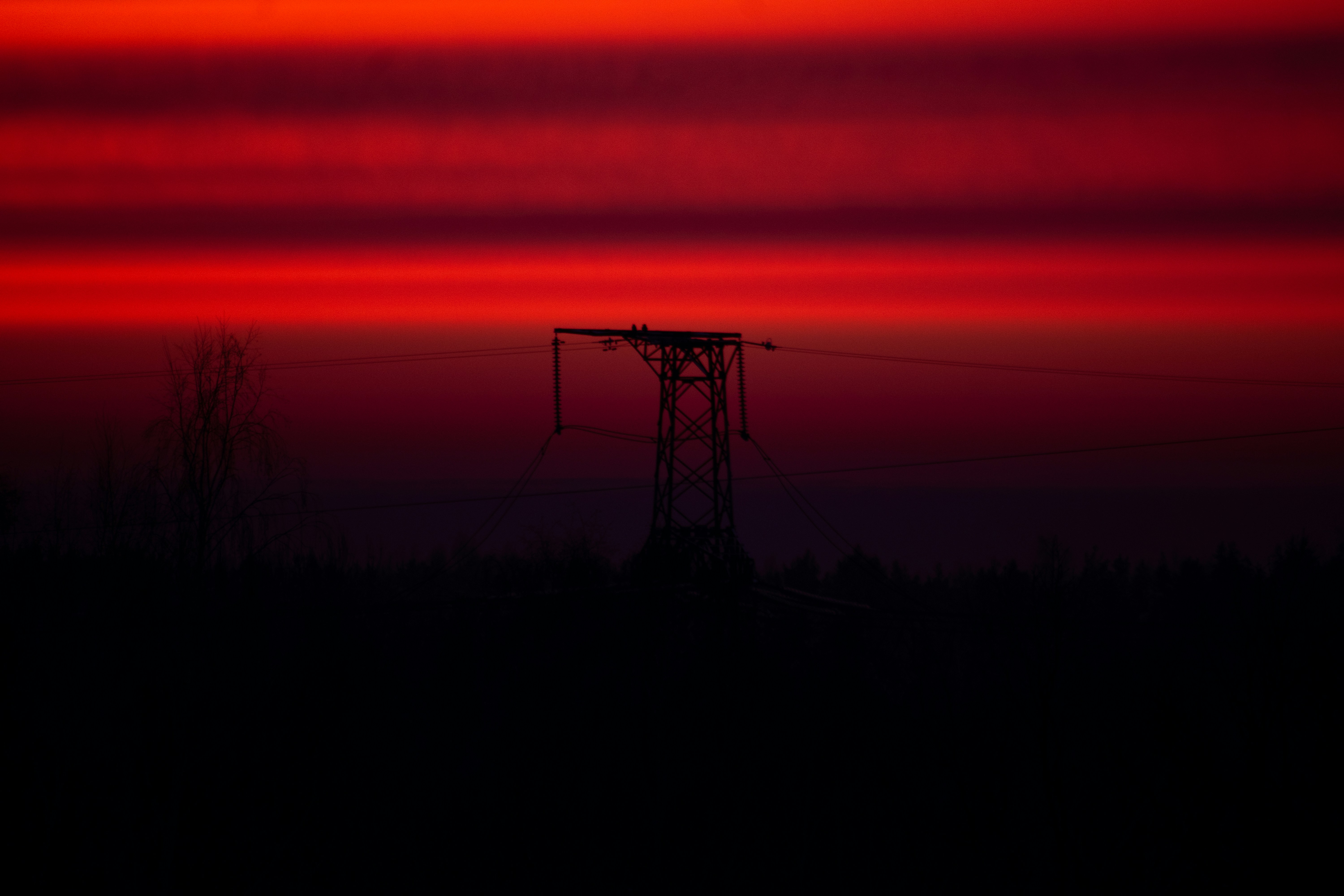 A red sky with a line of power lines in the foreground photo – Free ...