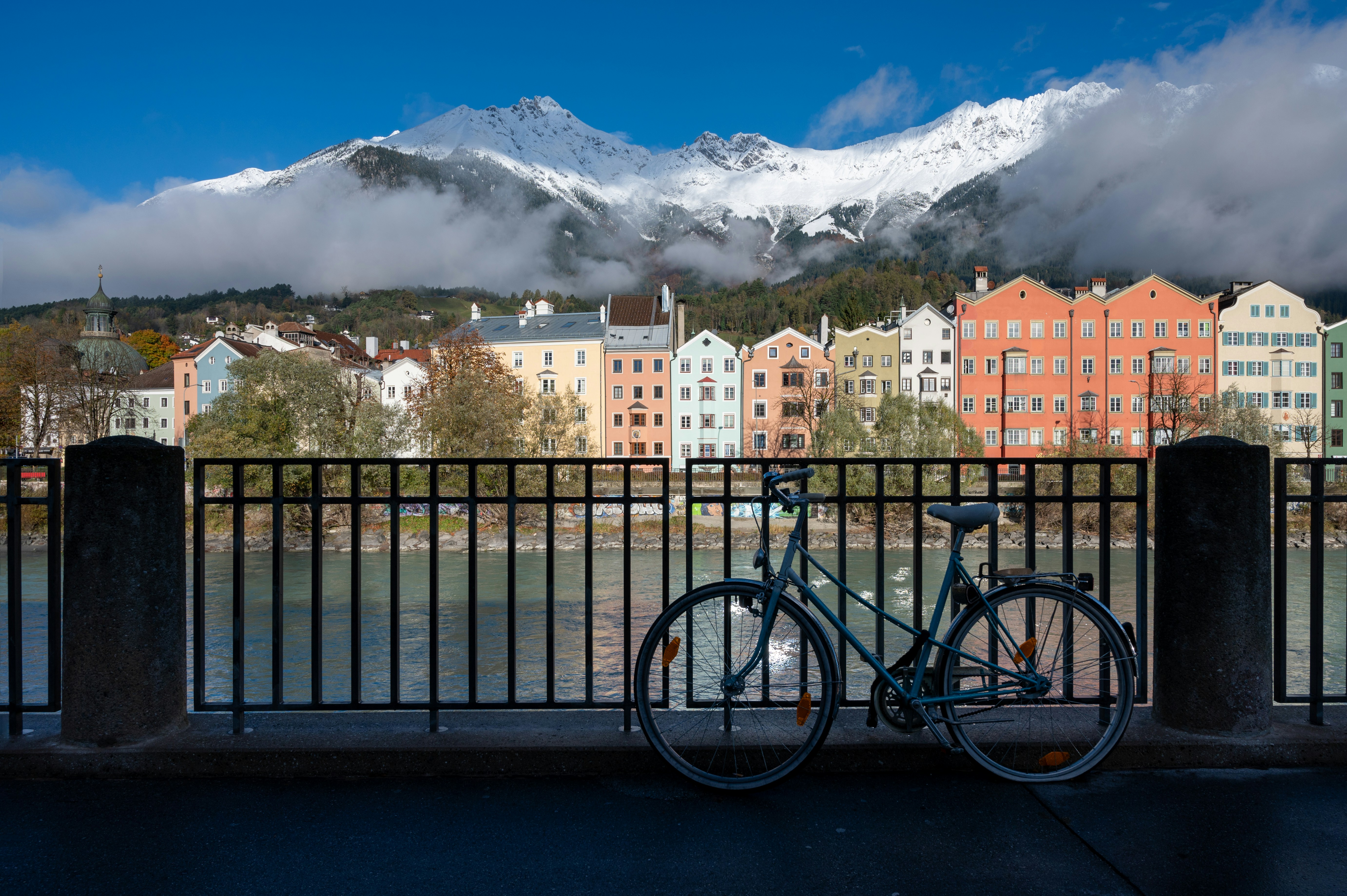 Bike on the railing: pastel riverside town under snow-kissed Alps