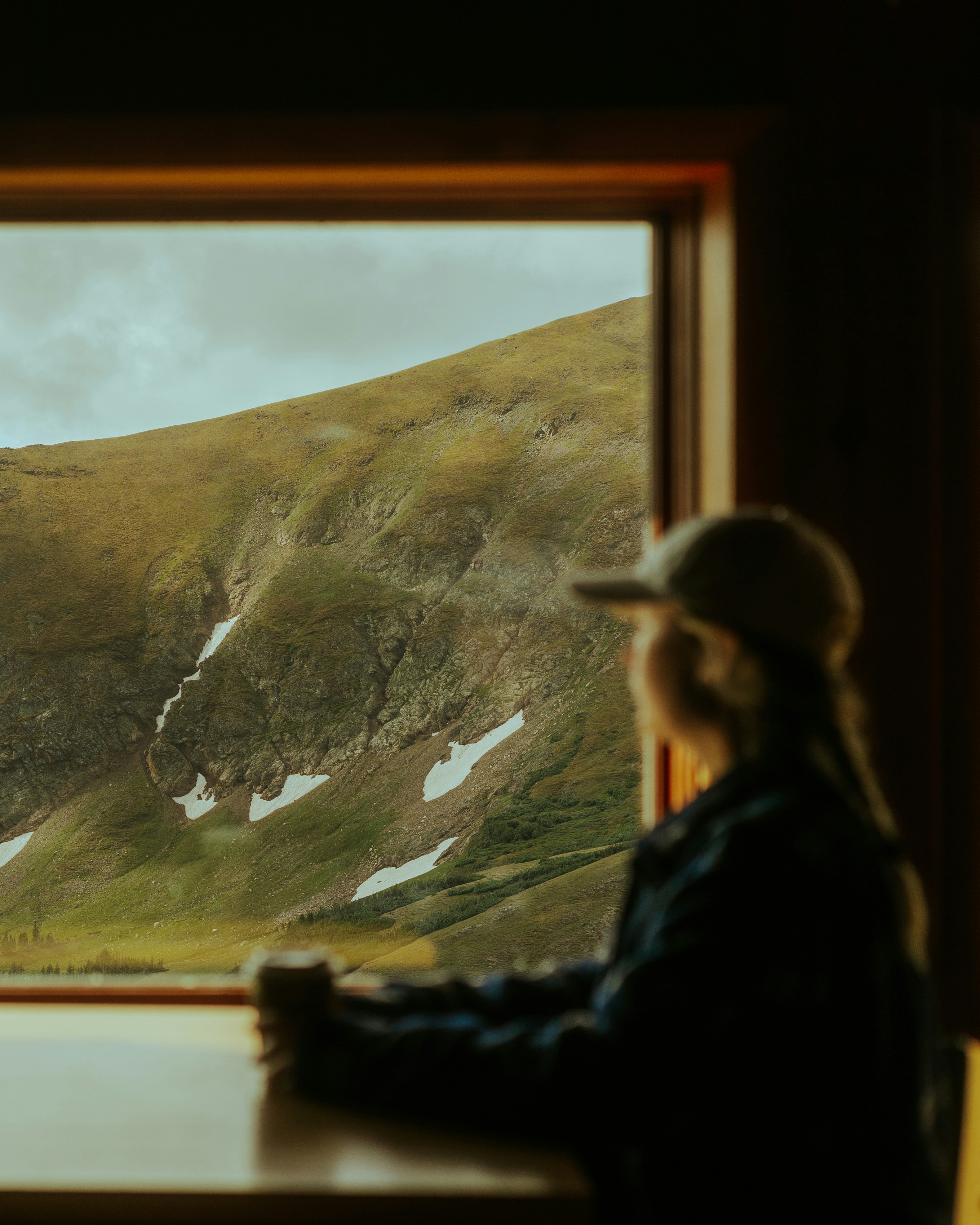 Windowed Summit: Mountain Light Framed by a Rustic Cabin