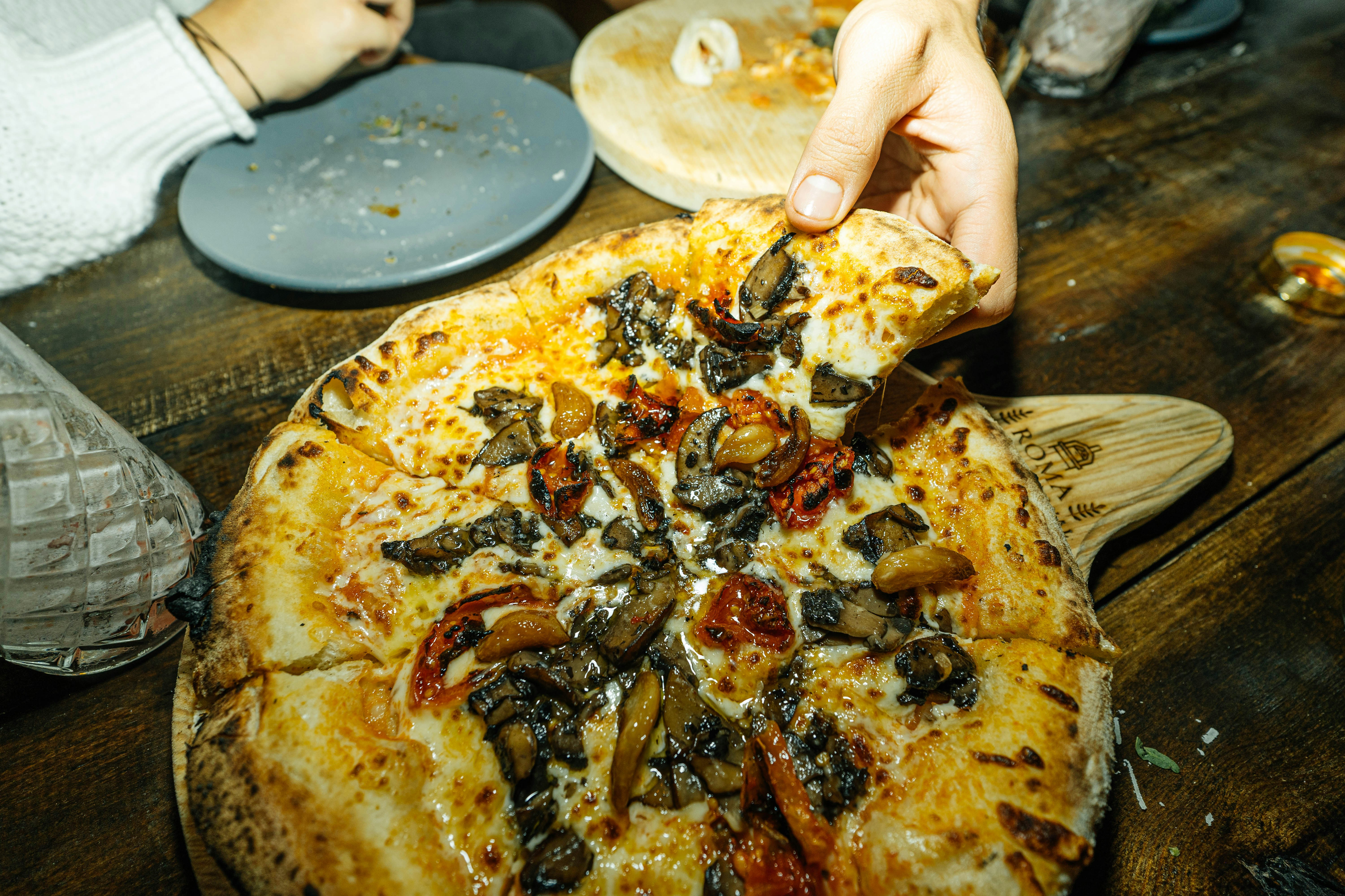 Slice Lift: A Hand Reaching for the Cheese-and-Mushroom Pizza