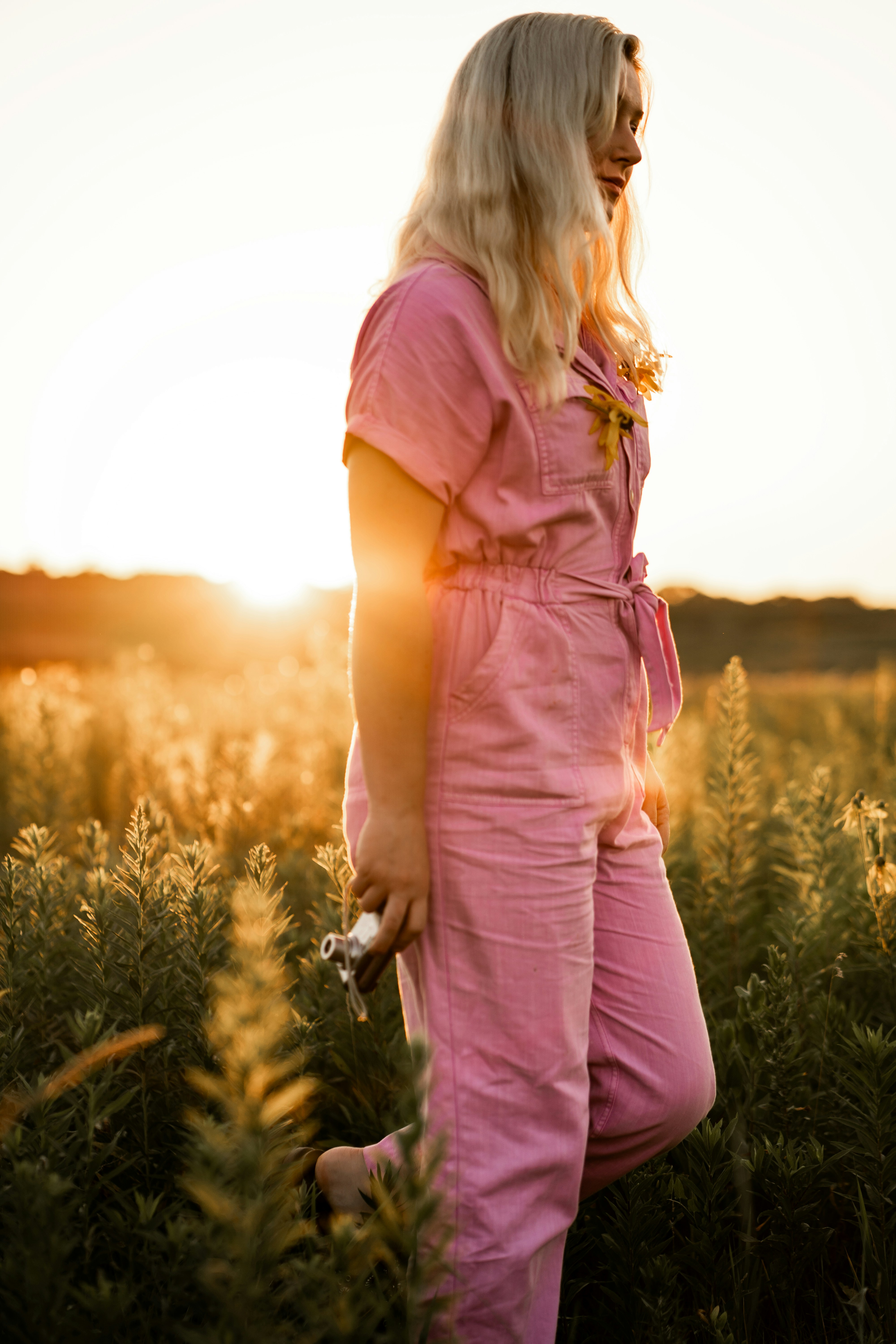 Una donna in una tuta rosa in piedi in un campo foto – Pantaloni ...