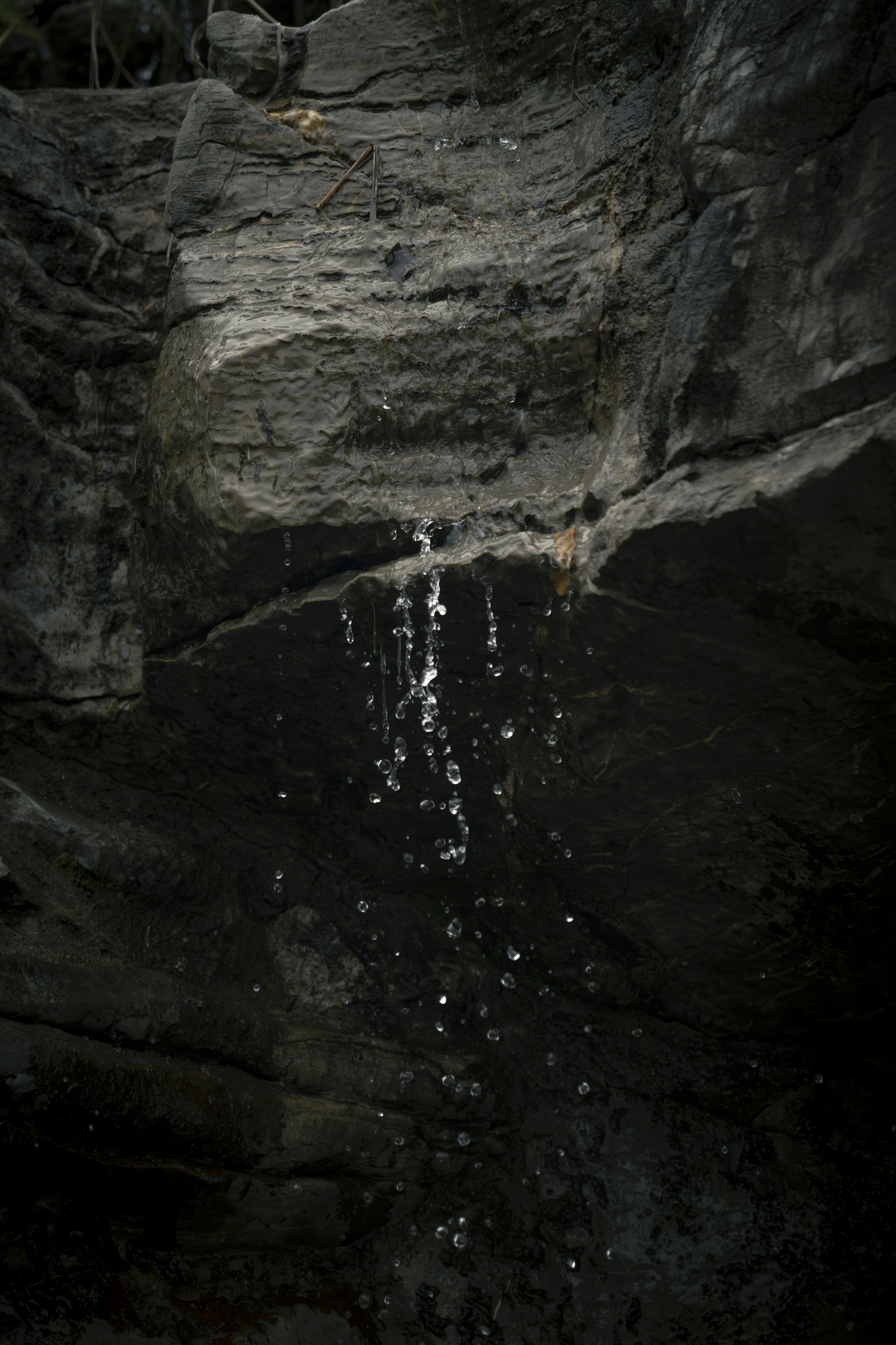 Midnight Drips: A Narrow Cascade from a Shadowed Rock Face