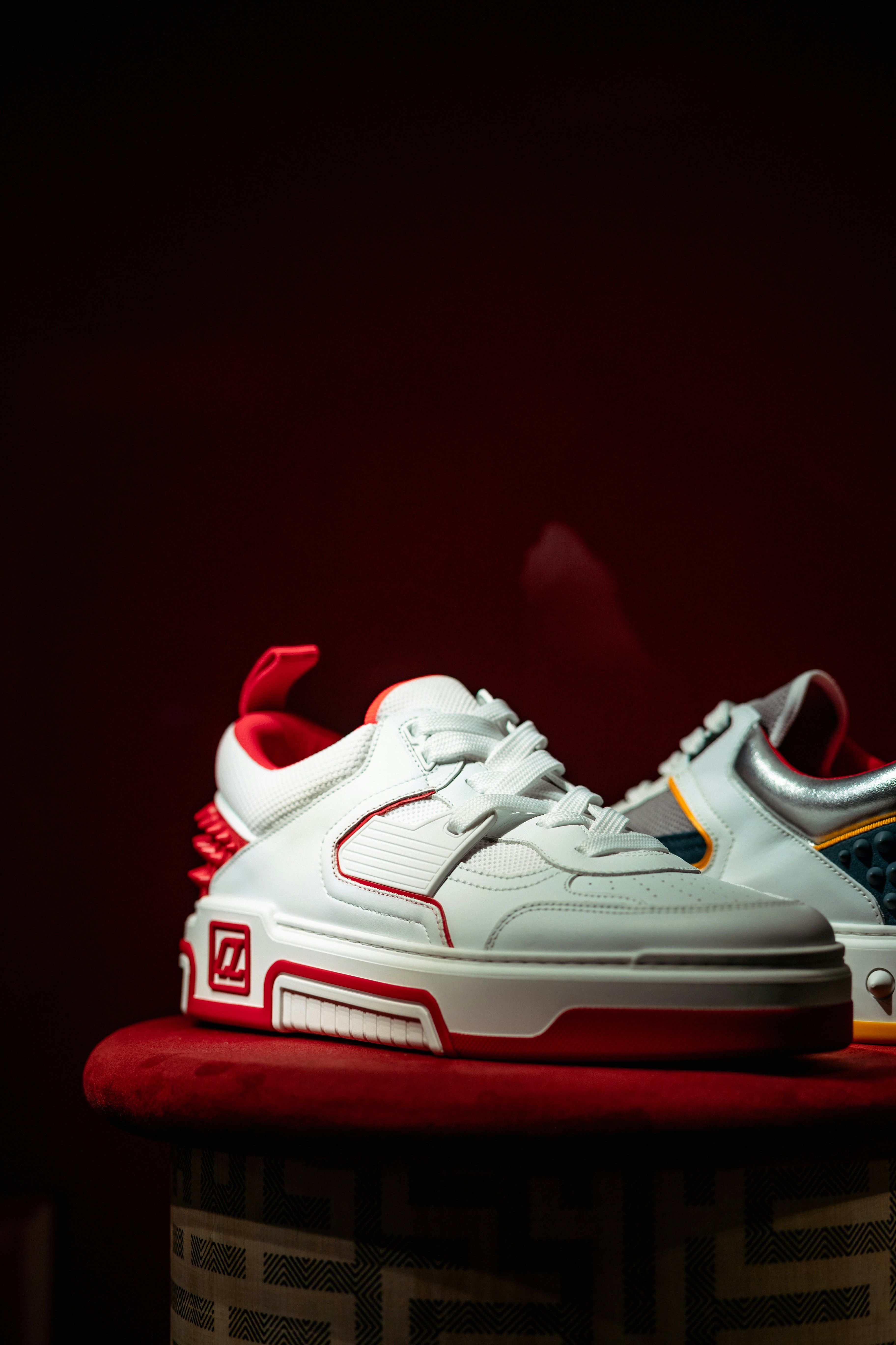 White sneakers on a red pedestal under moody lighting
