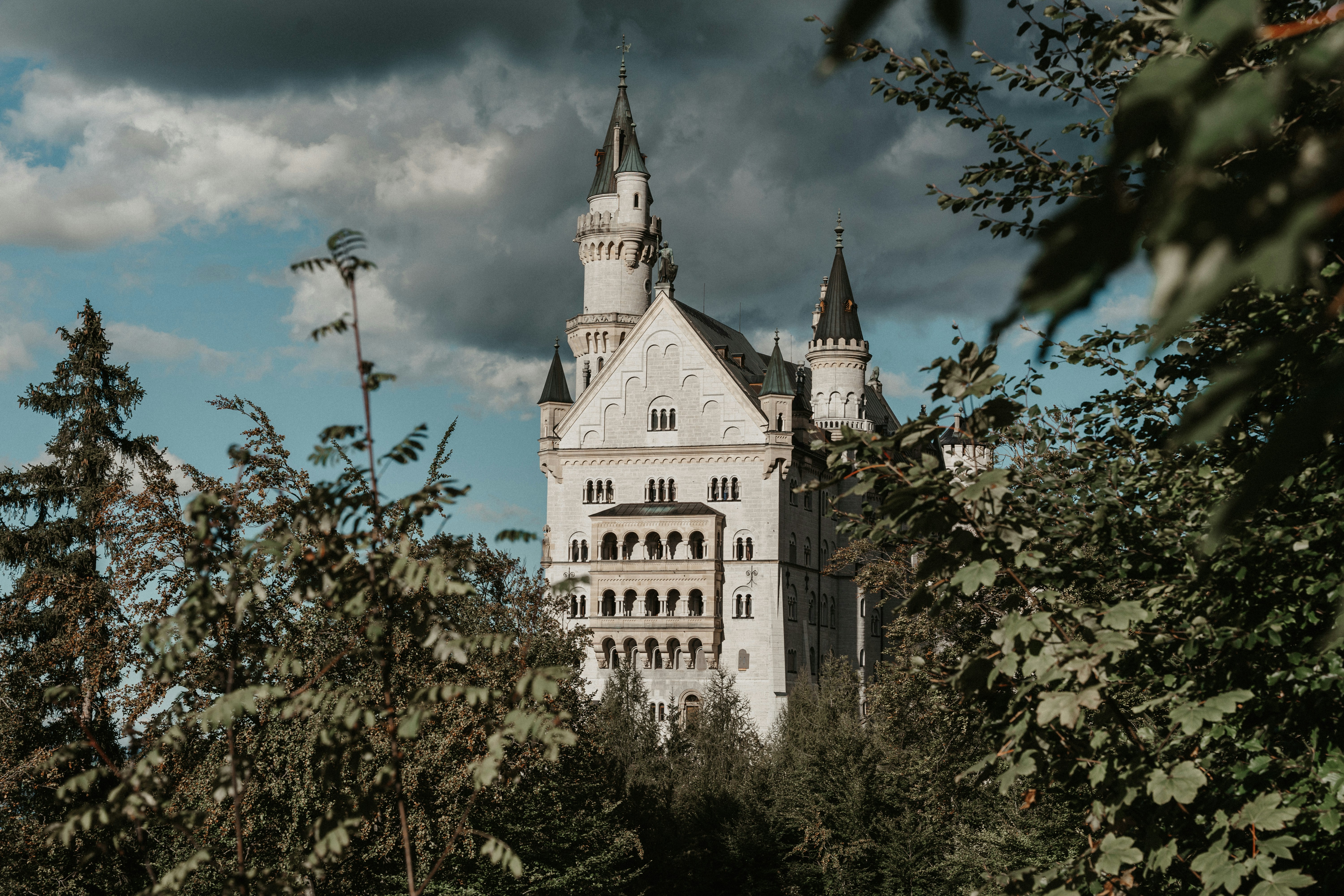 A large white castle surrounded by trees under a cloudy sky photo ...