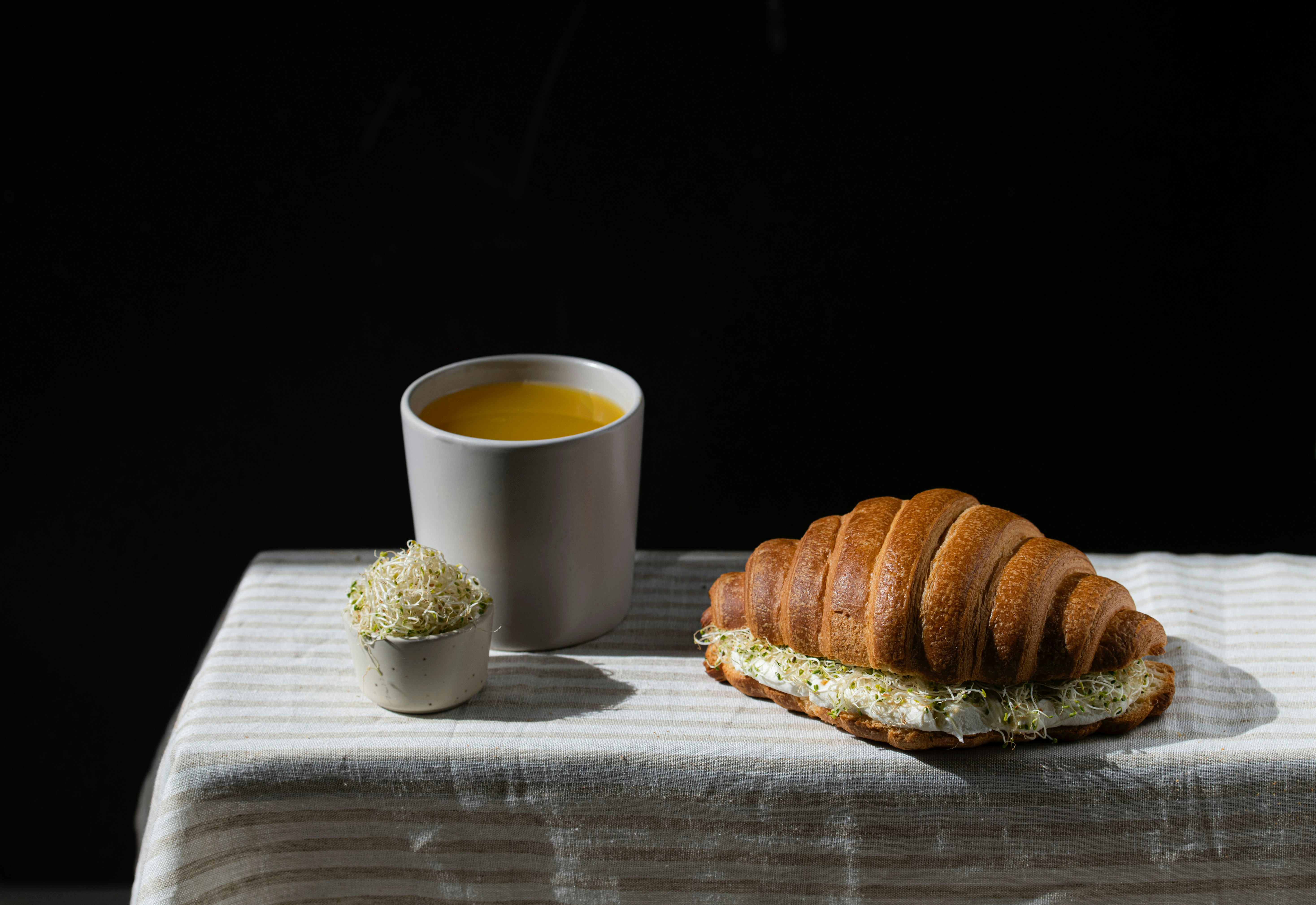 Sunlit Croissant Lunch on a Striped Table: A Quiet, Textured Still-Life