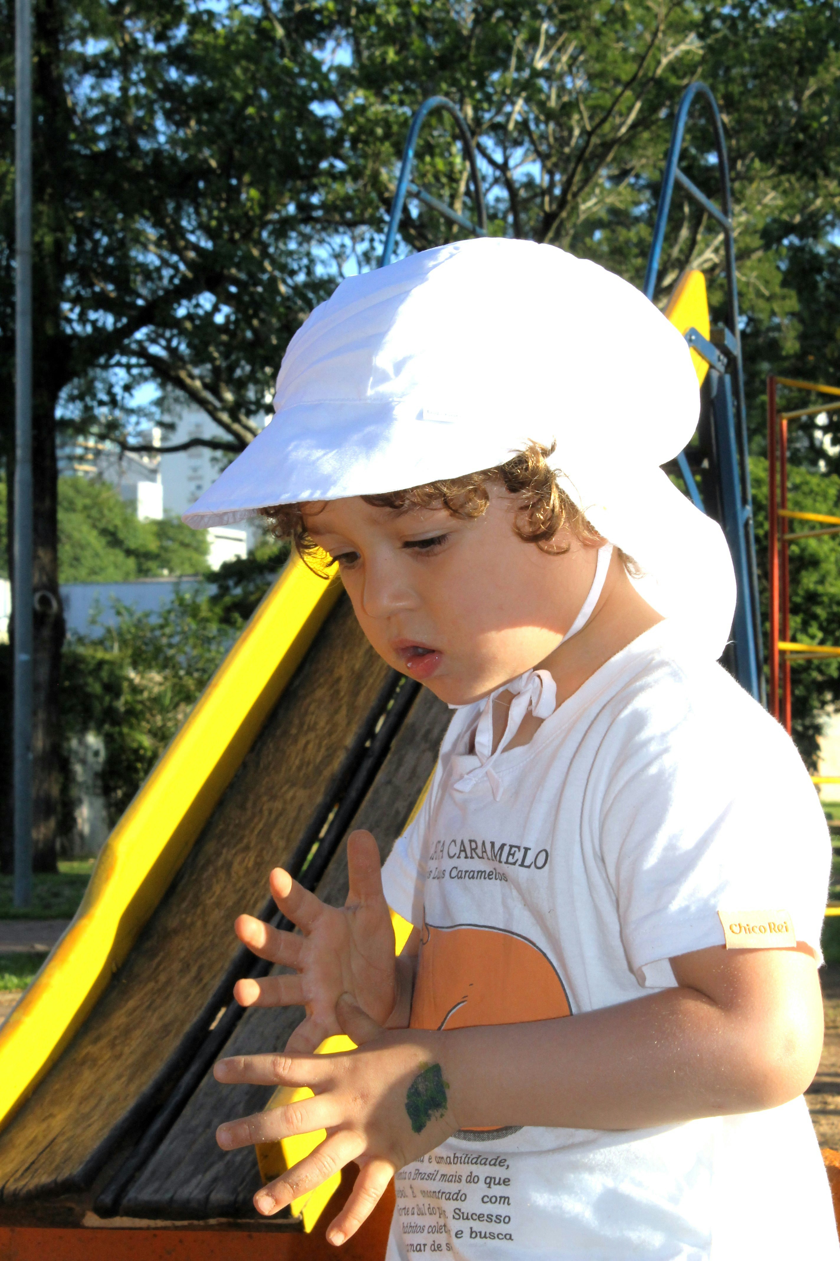 Sunlit Moment at the Playground: A Child in a White Hat