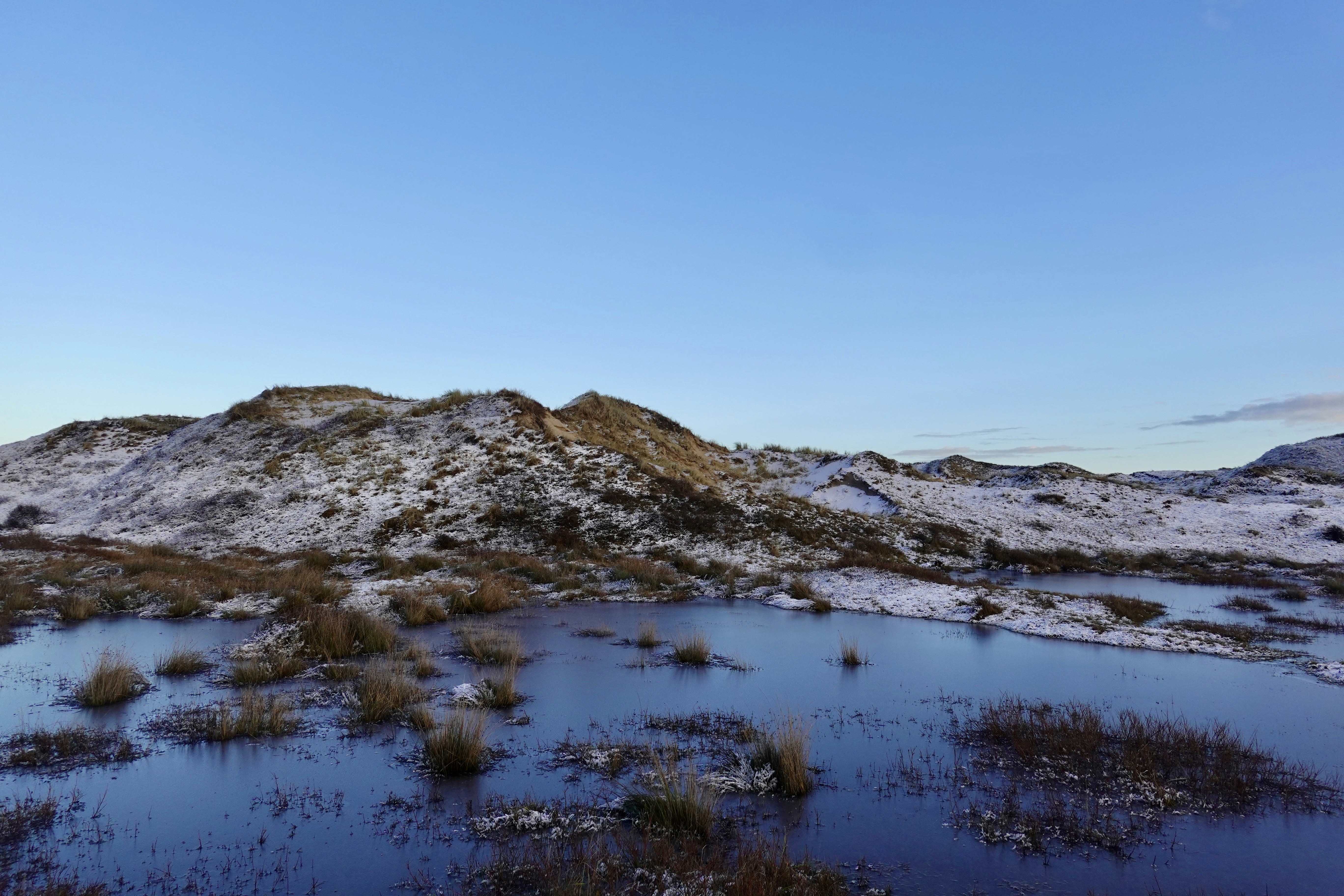 Coastal dunes after winter showers with the lower parts of the dune valleys filled with rainwater and having a thin layer of ice