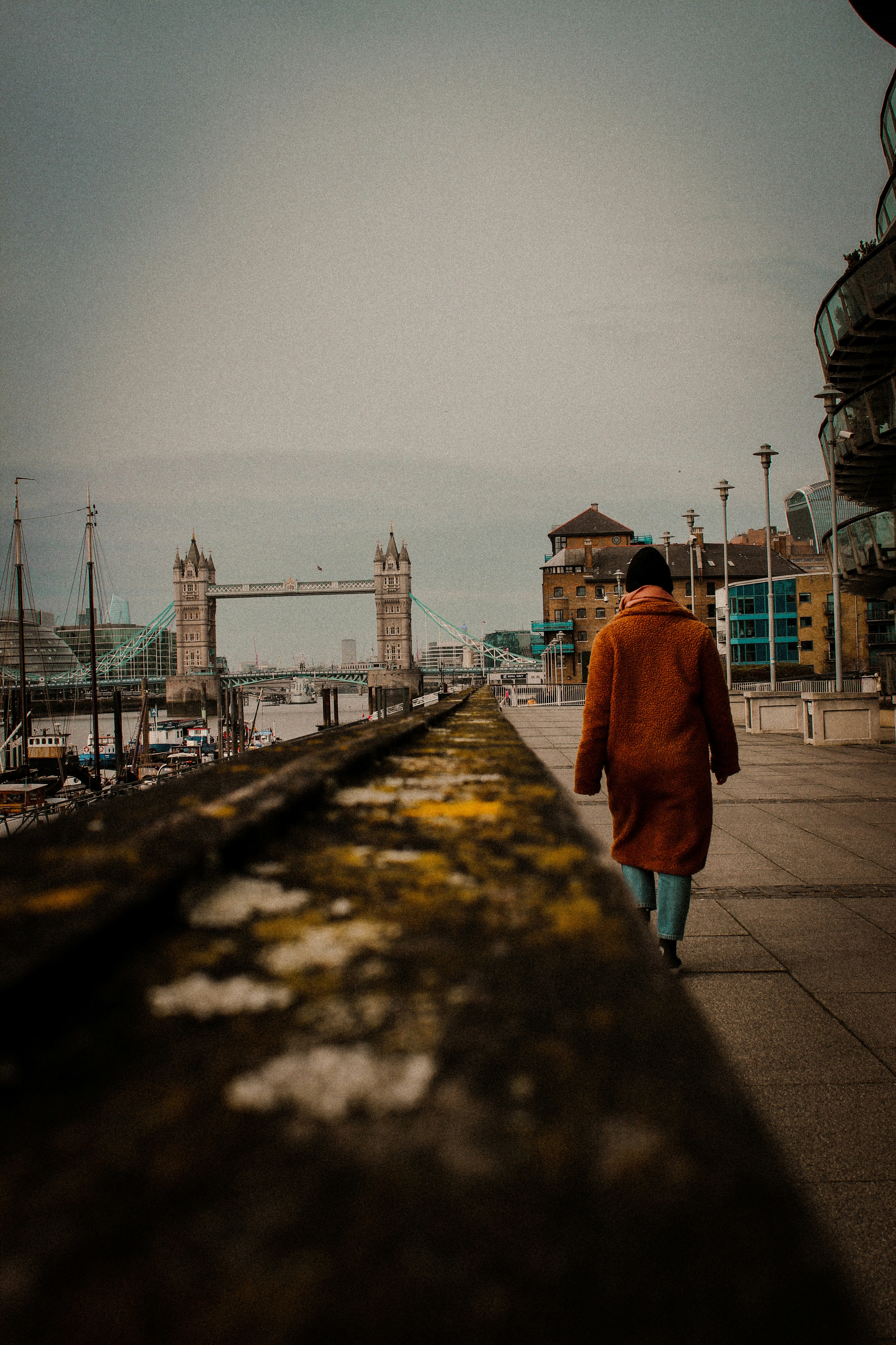 A man walking down a sidewalk next to a bridge photo – Free Street ...