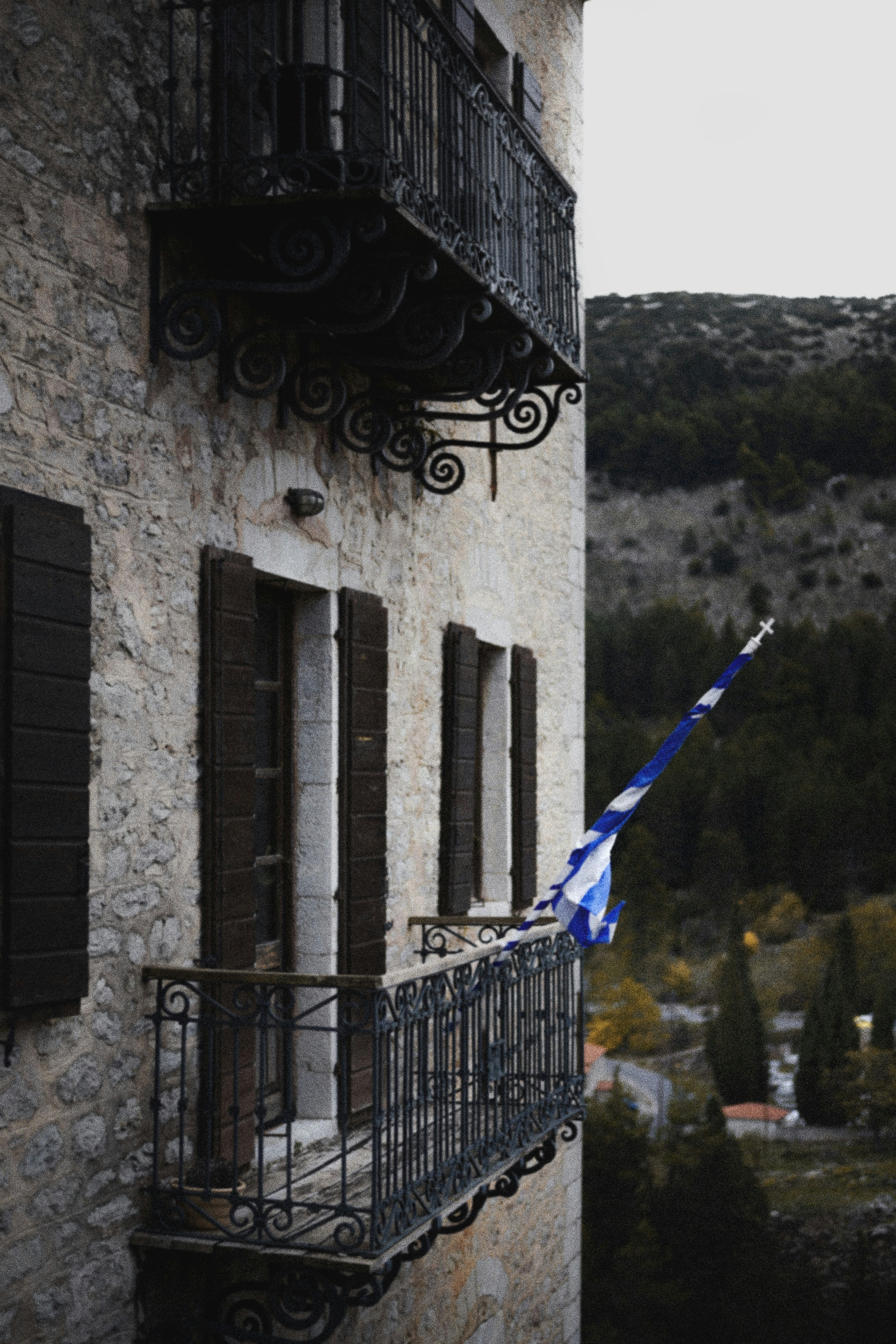 Flag on the Balcony: A Limestone Villa Framed by Hillside Pines