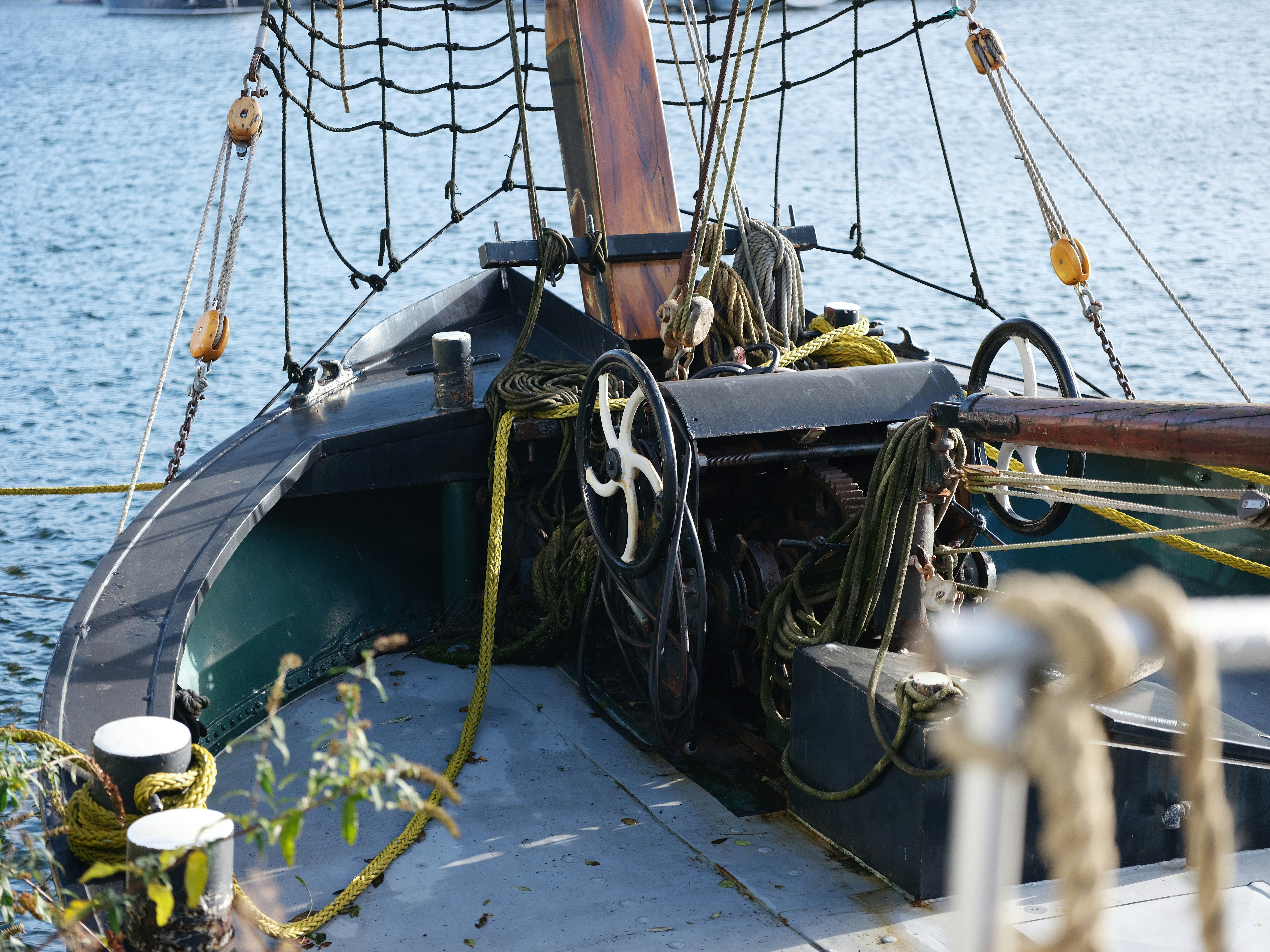 Close-up of a ship's deck with ropes and nautical equipment under a clear sky.