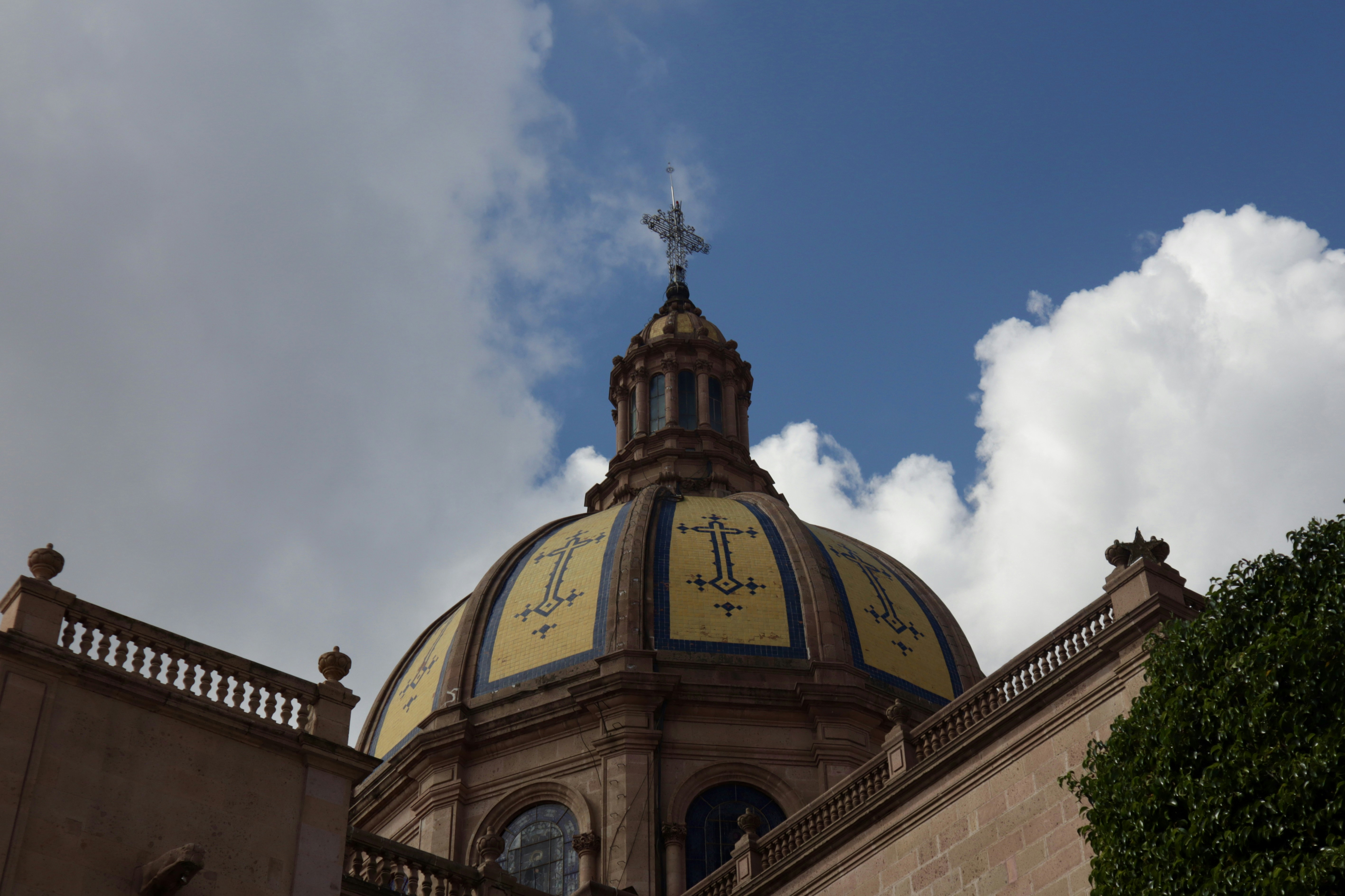 Majestic church dome with intricate designs set against a vivid blue sky and fluffy clouds.