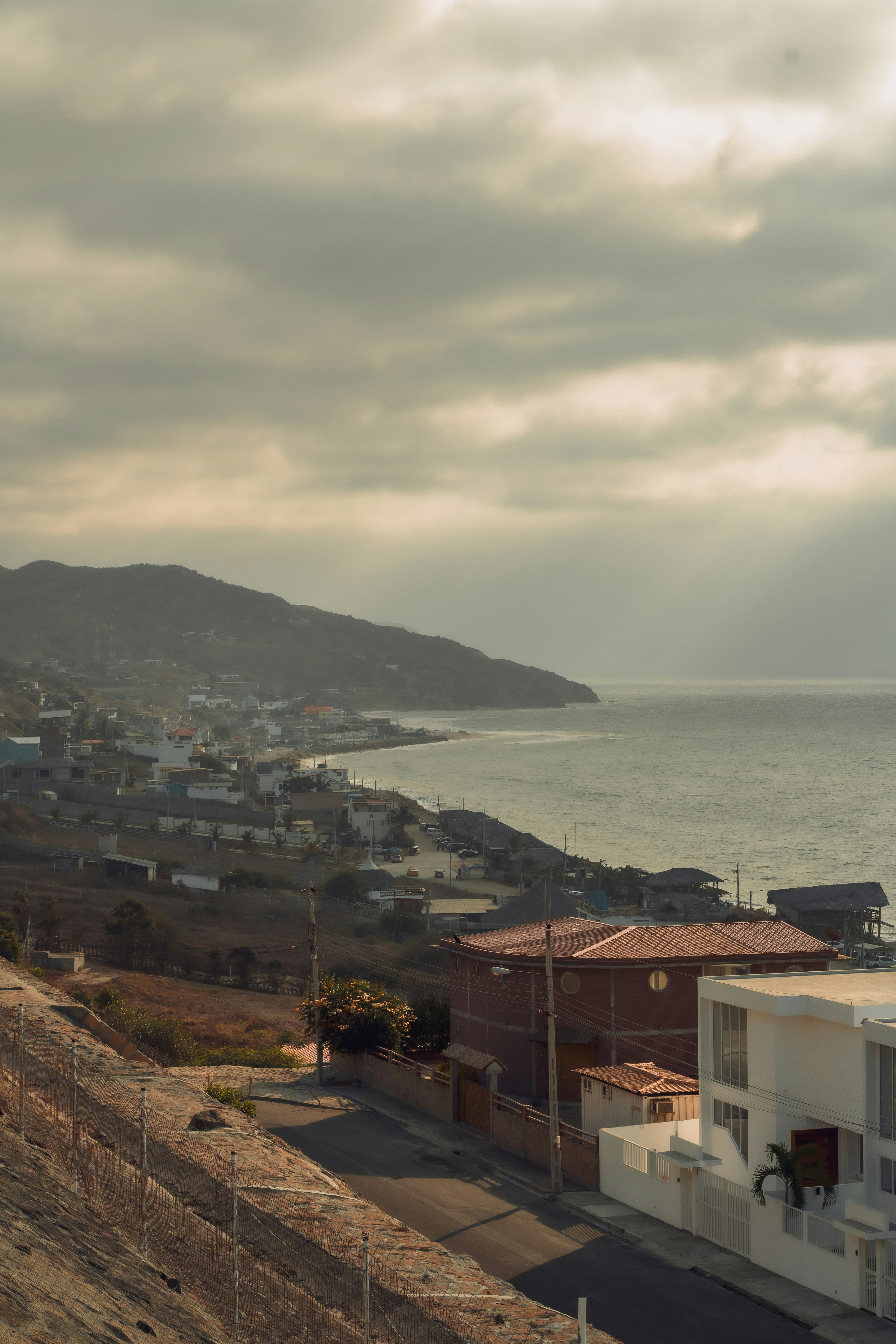 Hillside Village Reaching the Sea Under Sunlit Clouds