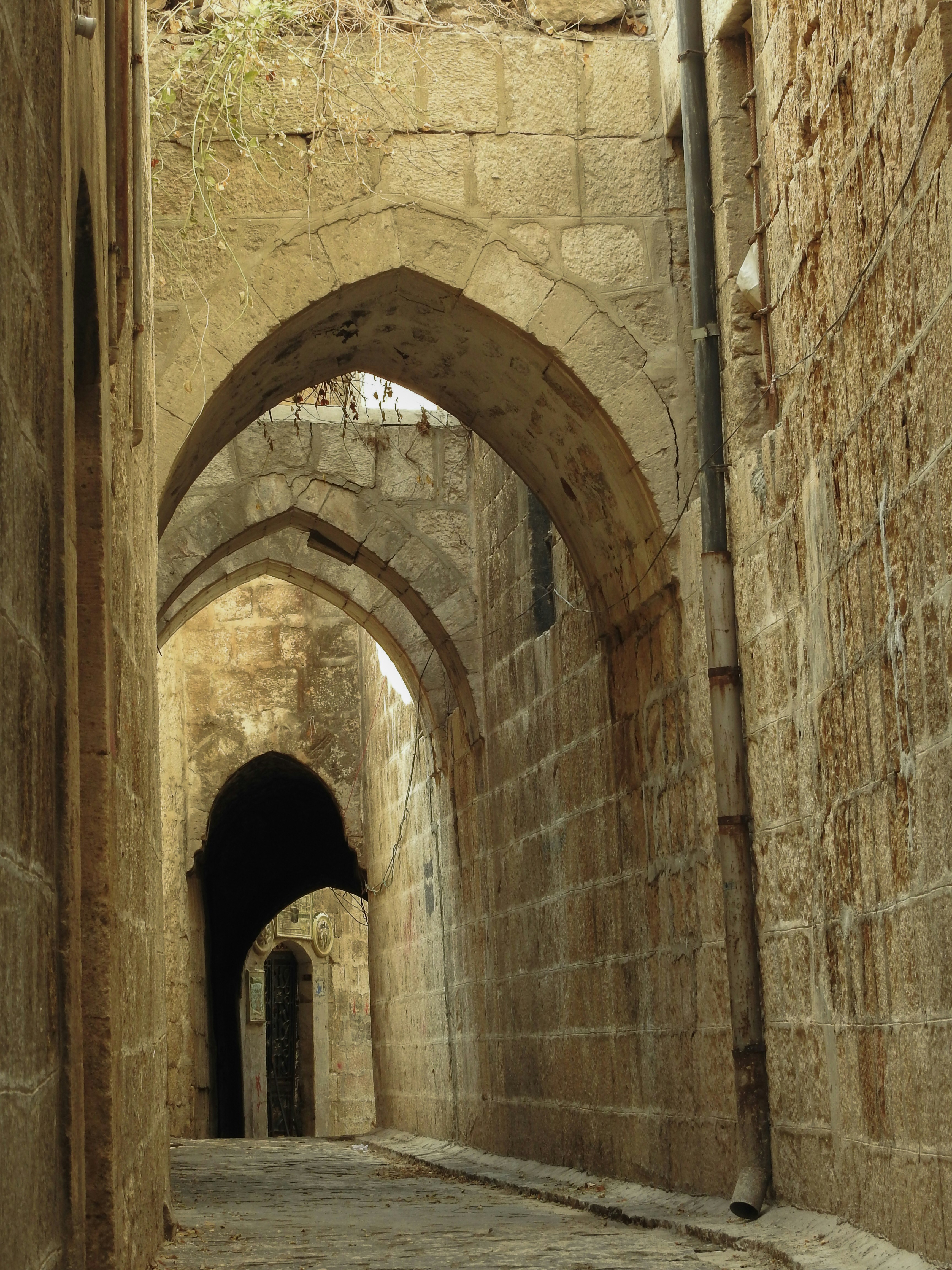 A narrow alley way with stone walls and arches photo – Free Building ...