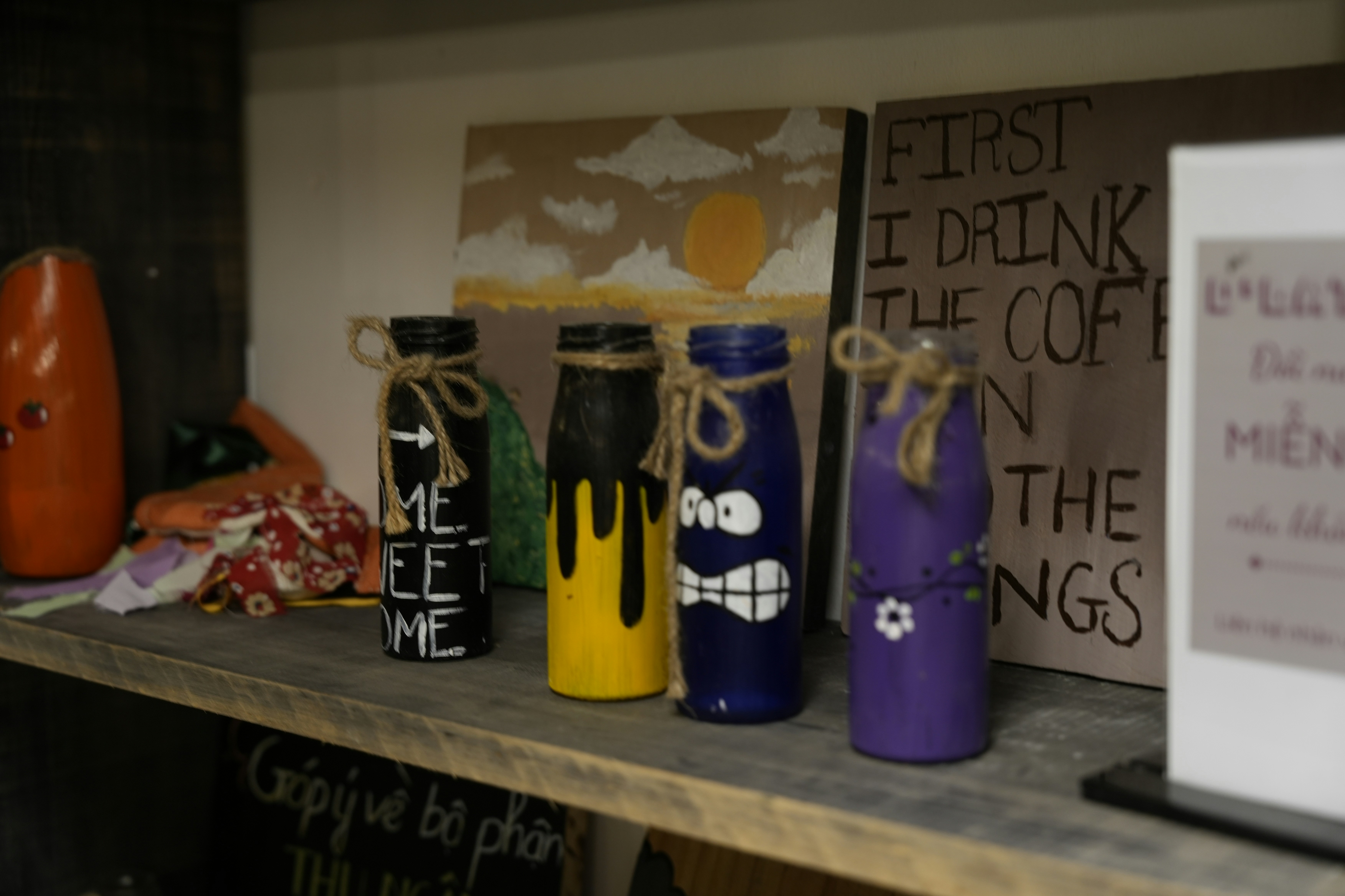Colorful painted bottles on a rustic shelf with handwritten notes