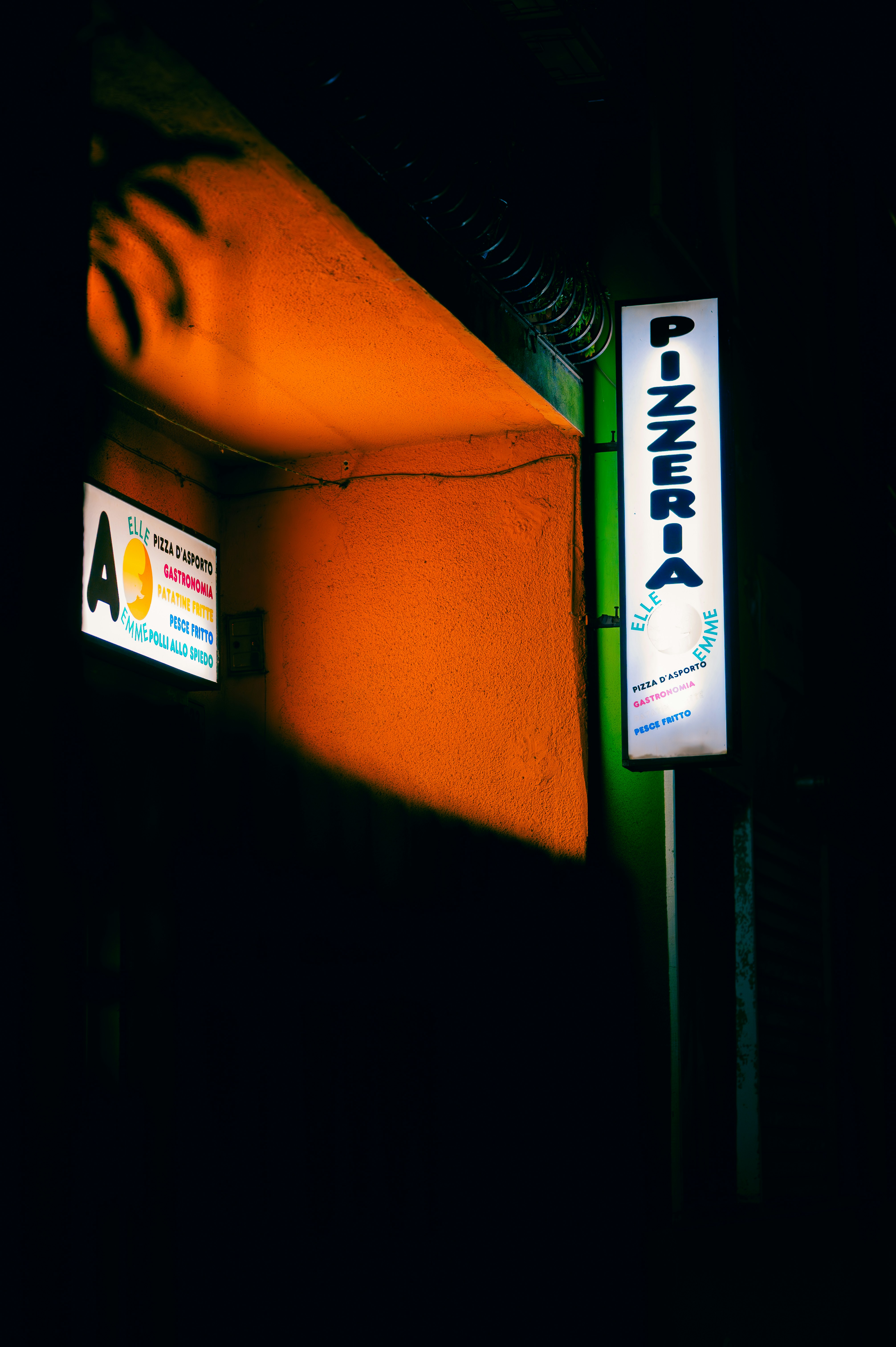Vertical Neon Sign Bathes a Nighttime Pizzeria in Orange Light