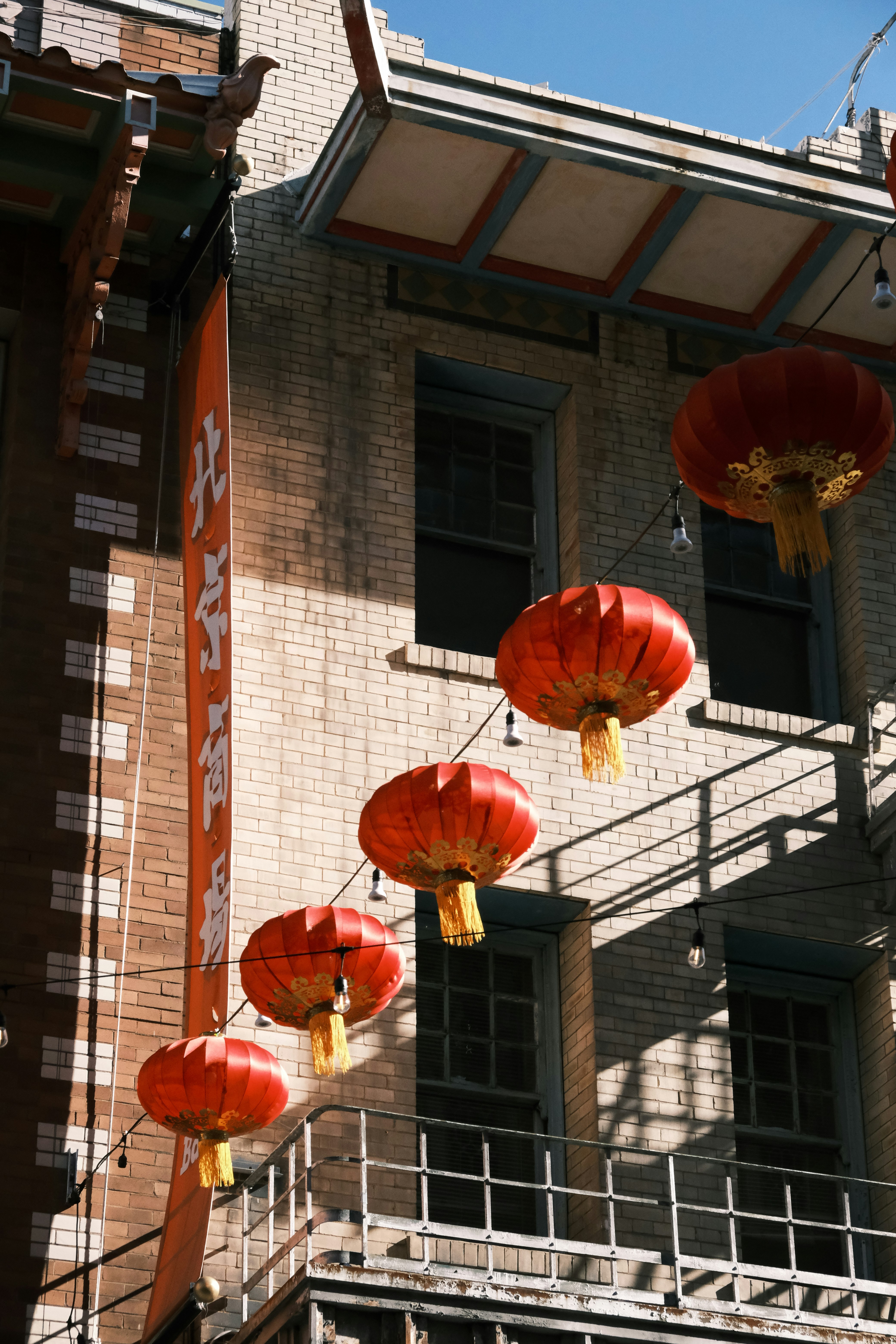Red Lanterns Draped Across a Sunlit Brick Balcony