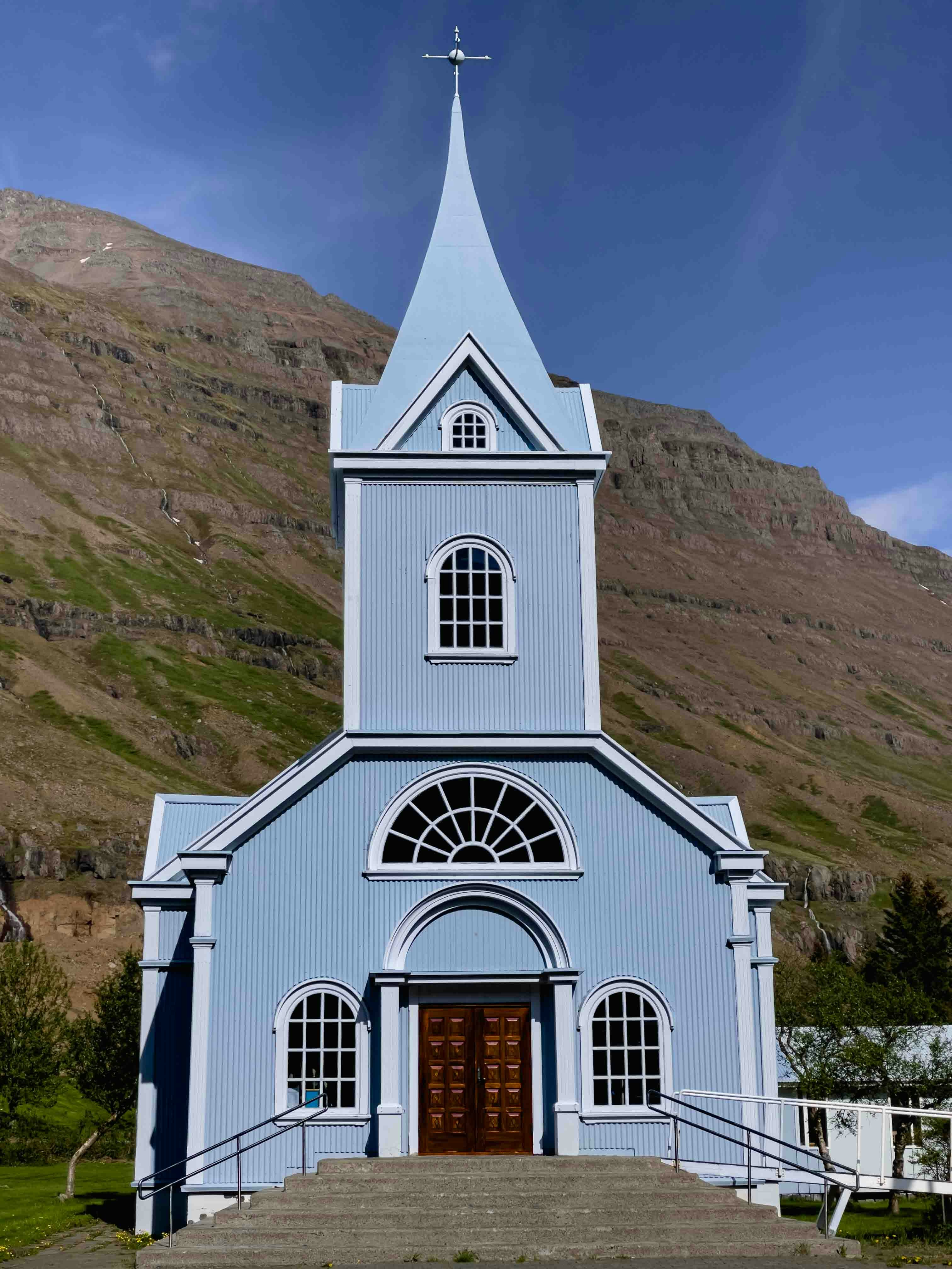 A blue church with a steeple and a cross on top photo – Free ...