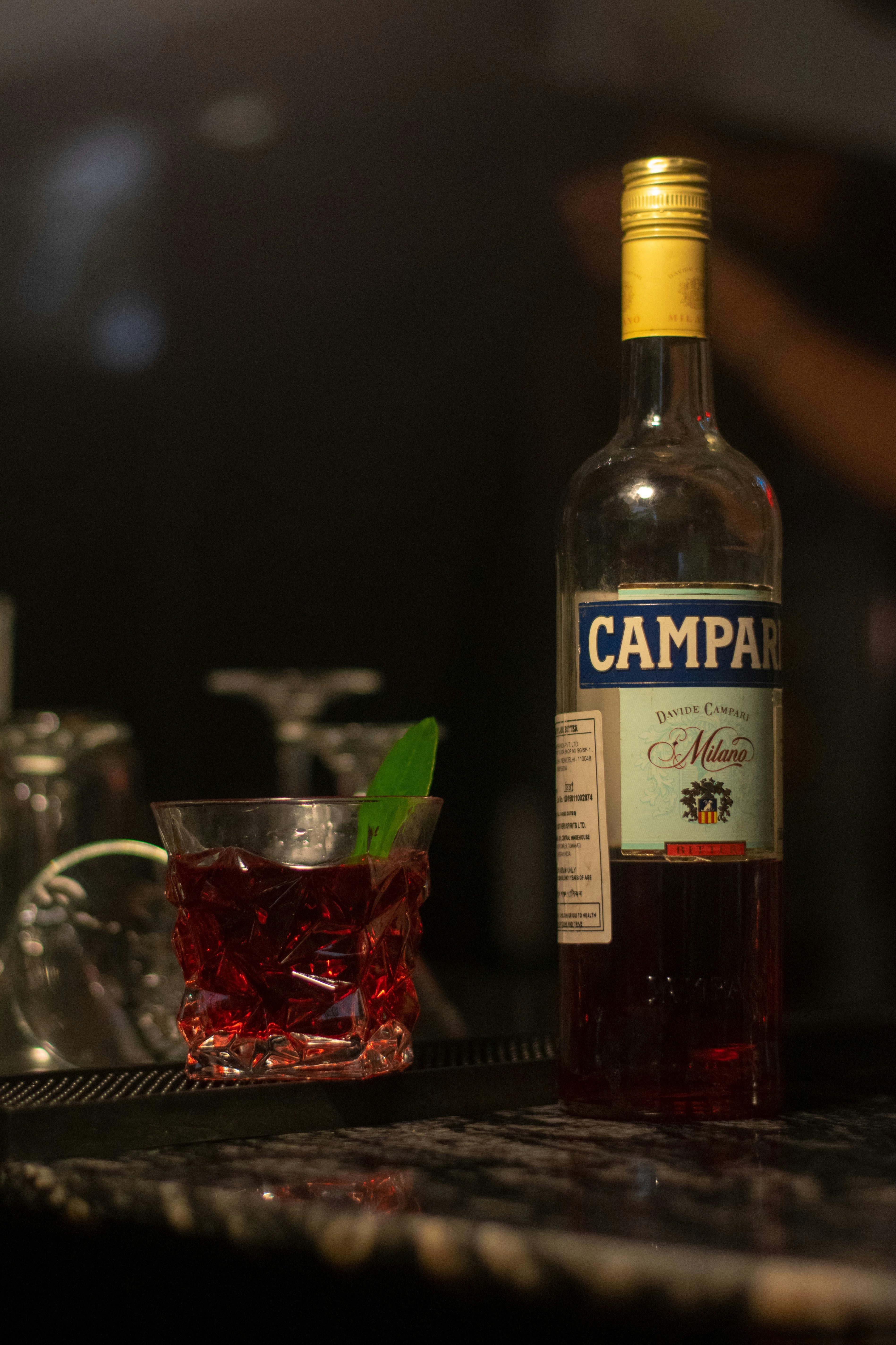 A bottle of campari next to a glass of wine photo – Free Alcohol Image ...