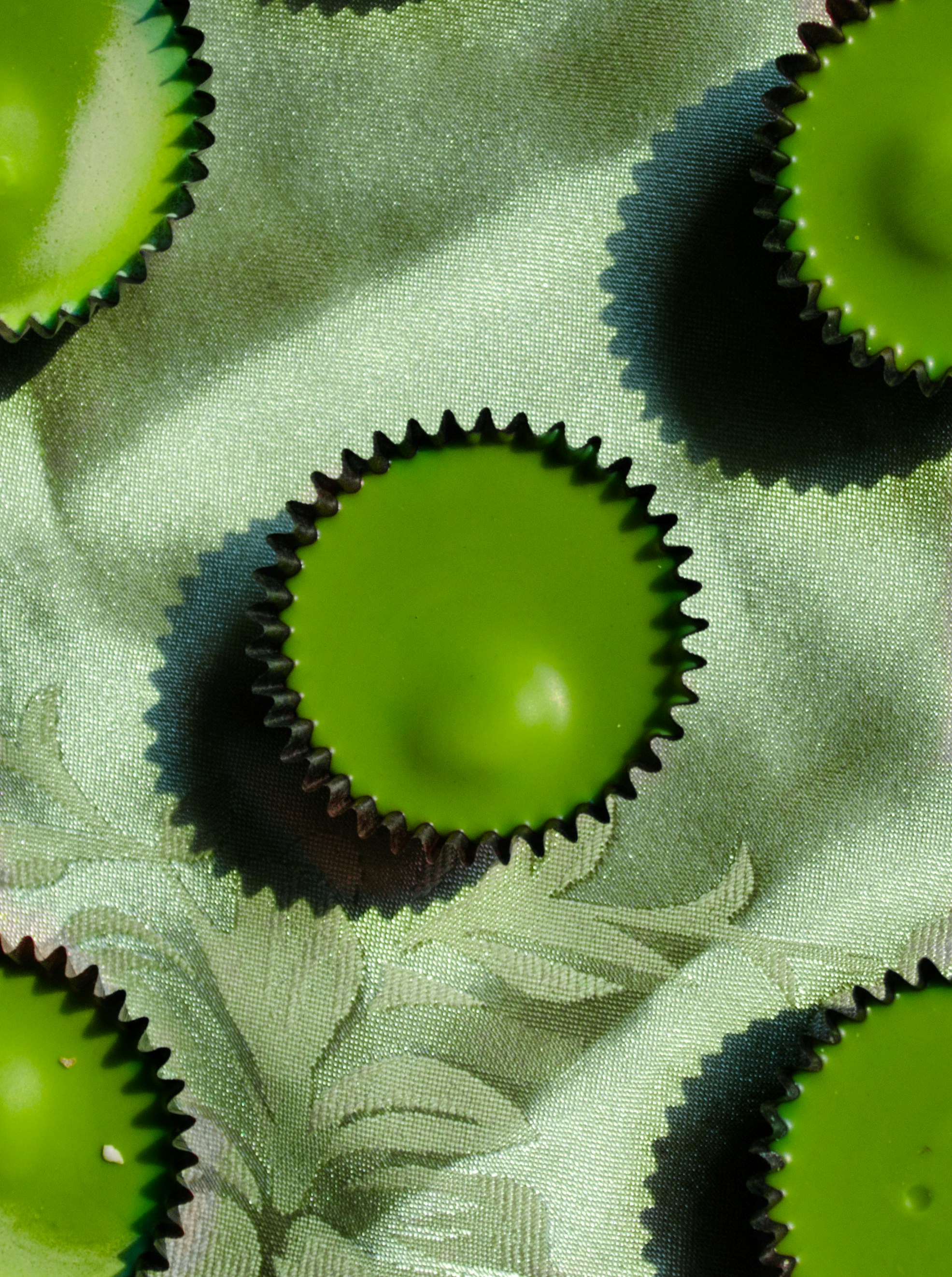 Emerald Serrations: Macro Portrait of Lime-Green Bottle Caps on Satin