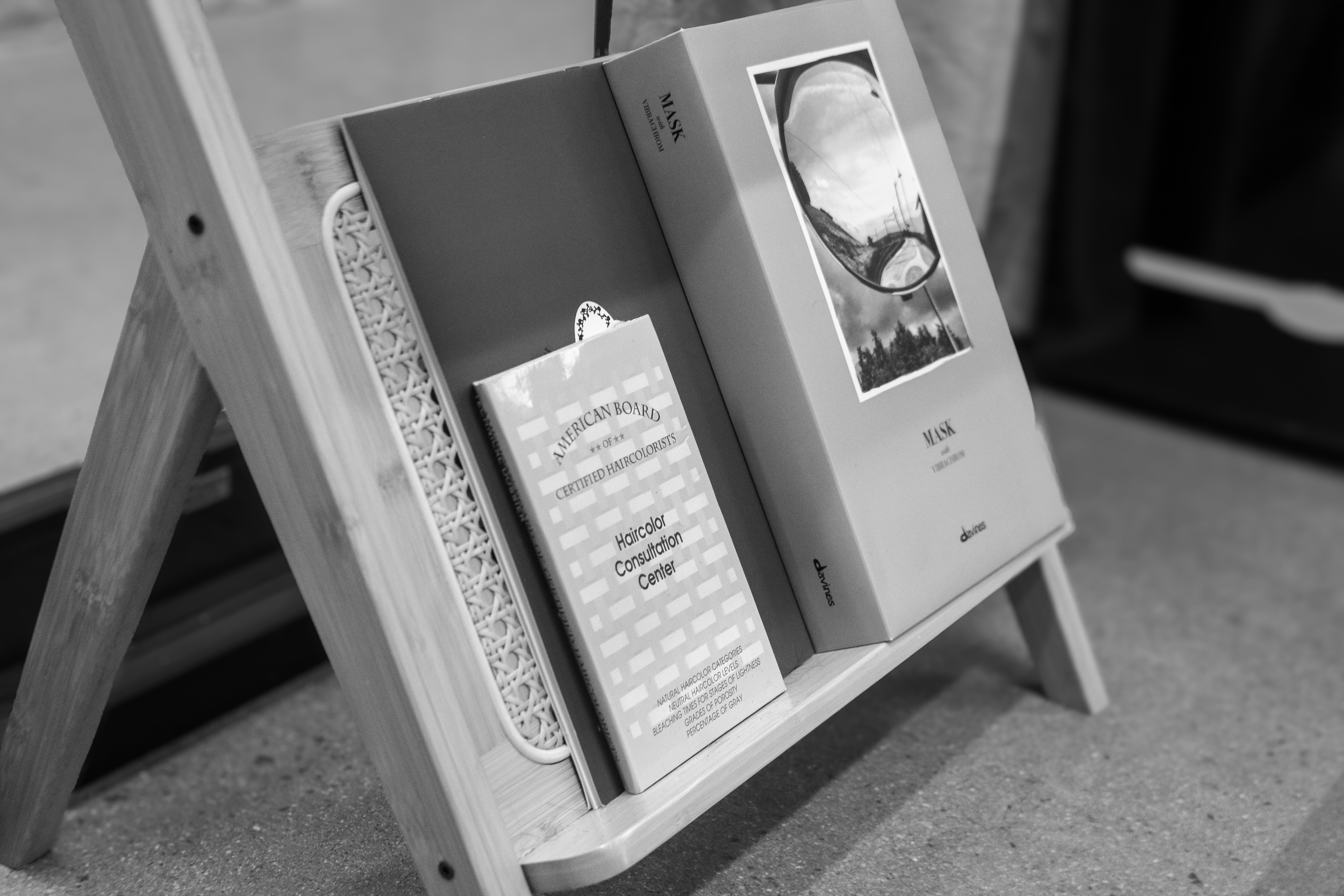 A wooden bookstand displaying two elegantly designed books, one featuring a reflective cover. The monochrome aesthetic highlights the simplicity and elegance of the arrangement.