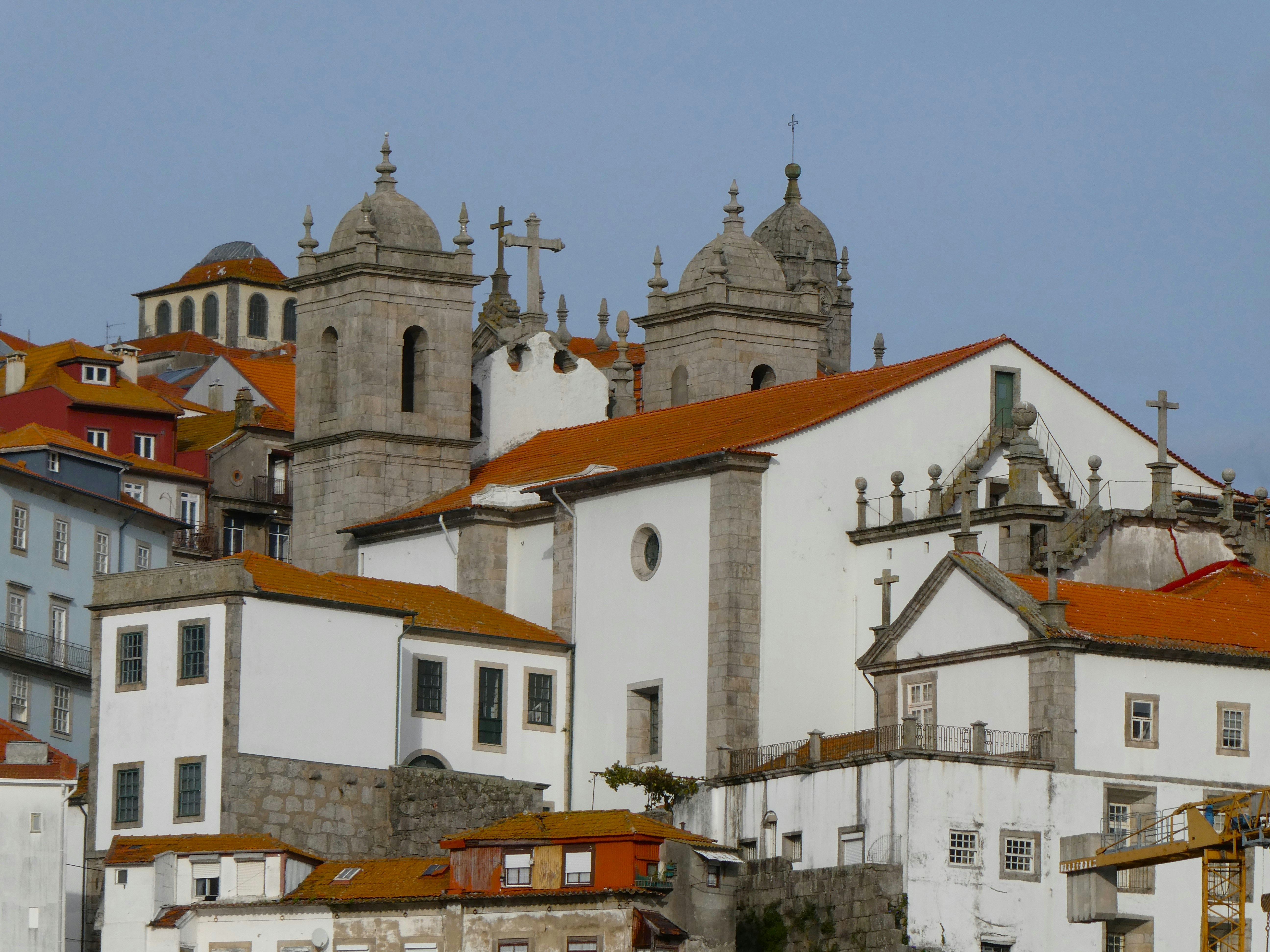 Cluster of white buildings with red roofs and stone towers under a clear sky.