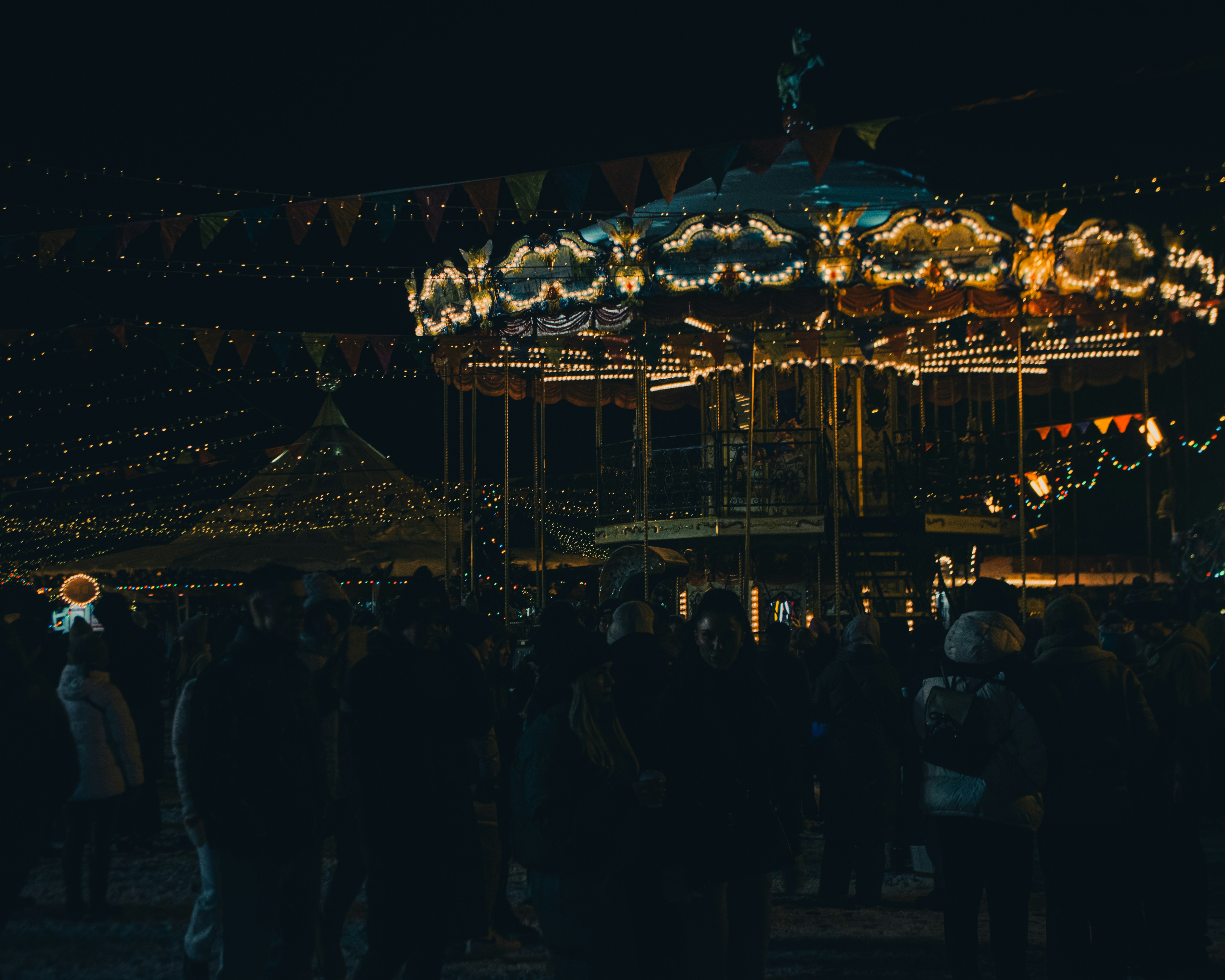 A group of people standing around a merry go round photo – Free ...