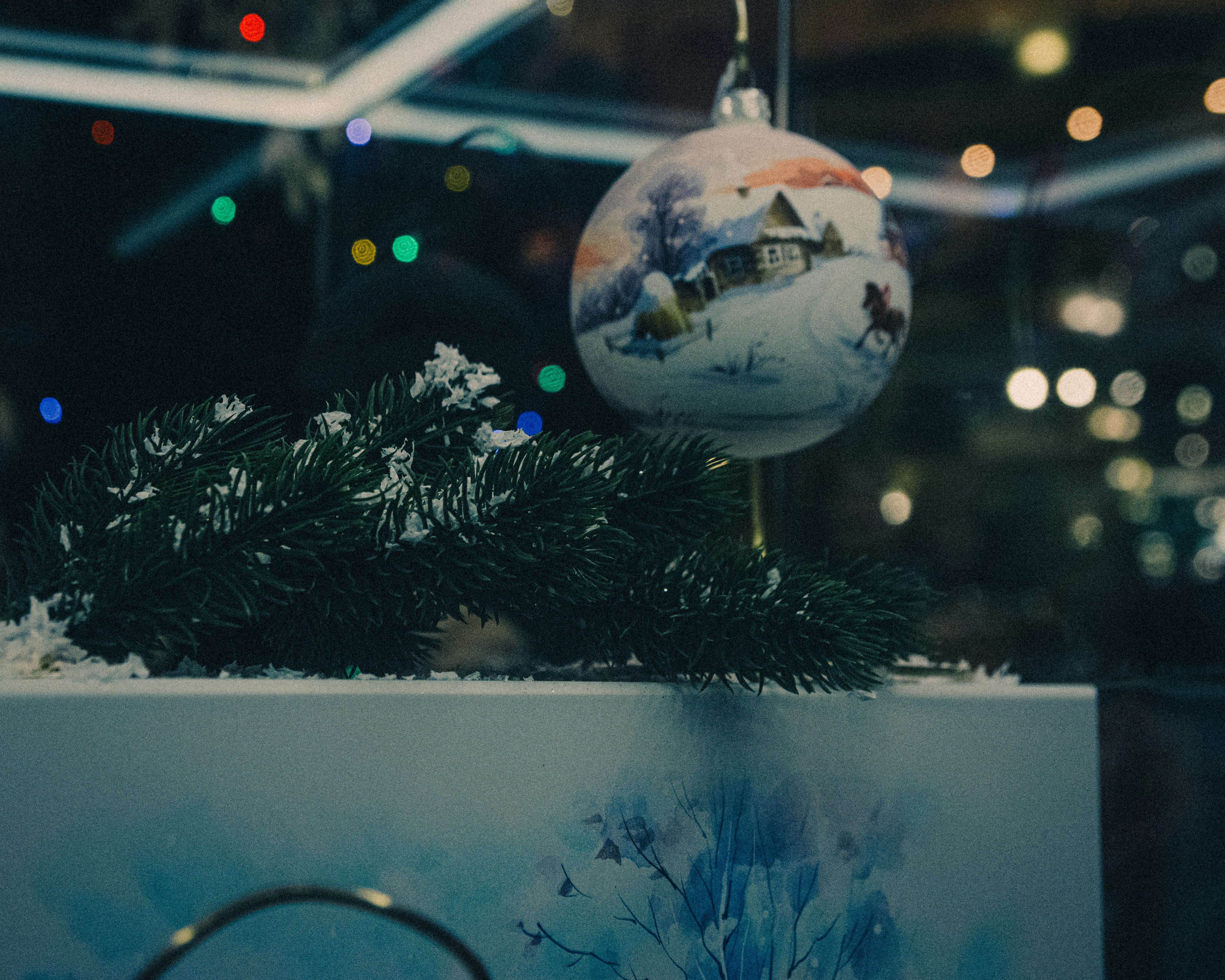 Ornament above a snow-dusted pine with festive glow